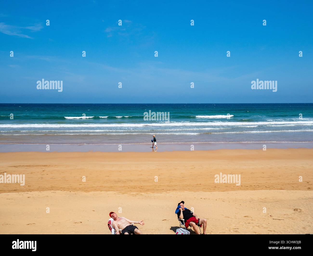 May 20, 2025, Zarautz, Spain: Two men seen sun bathing while a woman is ...