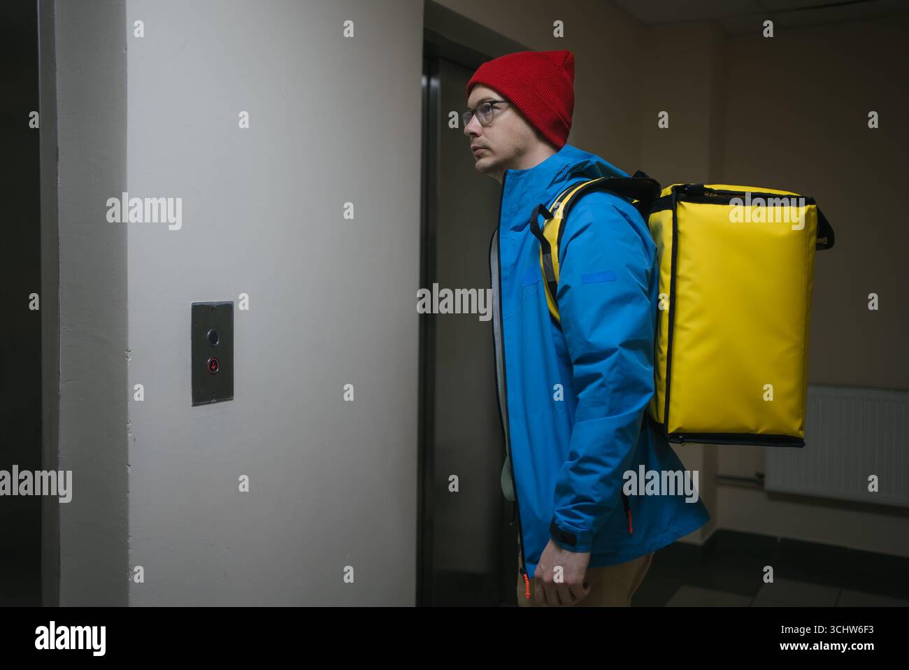 Delivery man wearing blue jacket and red hat is waiting for the ...