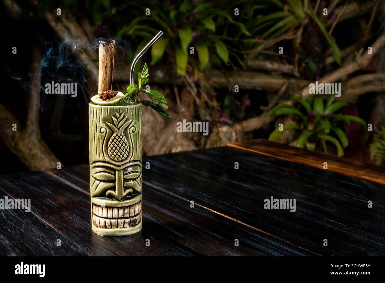 An intriguing smoked cocktail in a green ceramic tiki glass, with a ...