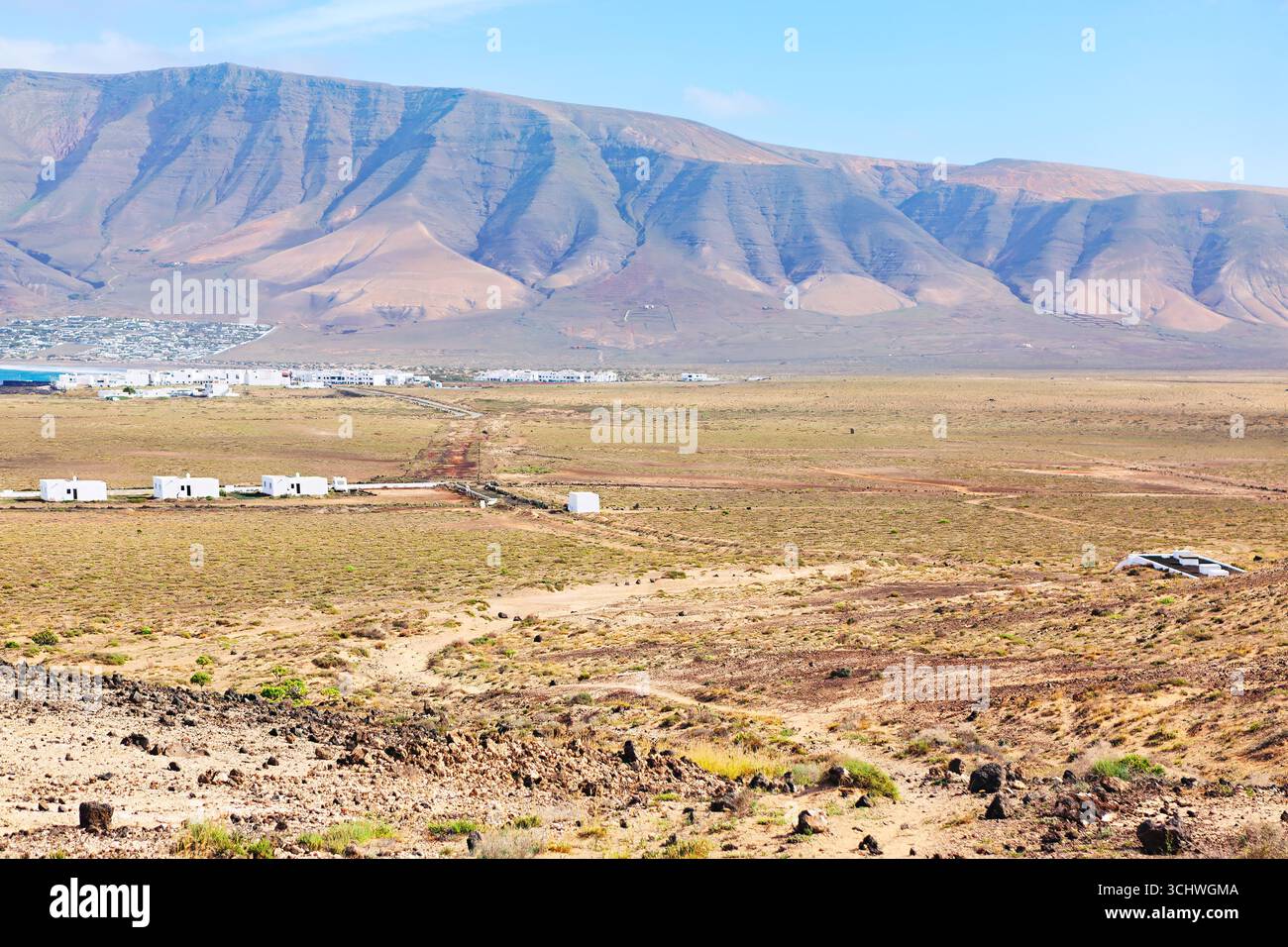 Arid terrain stretches toward rugged volcanic peaks, with compact town ...