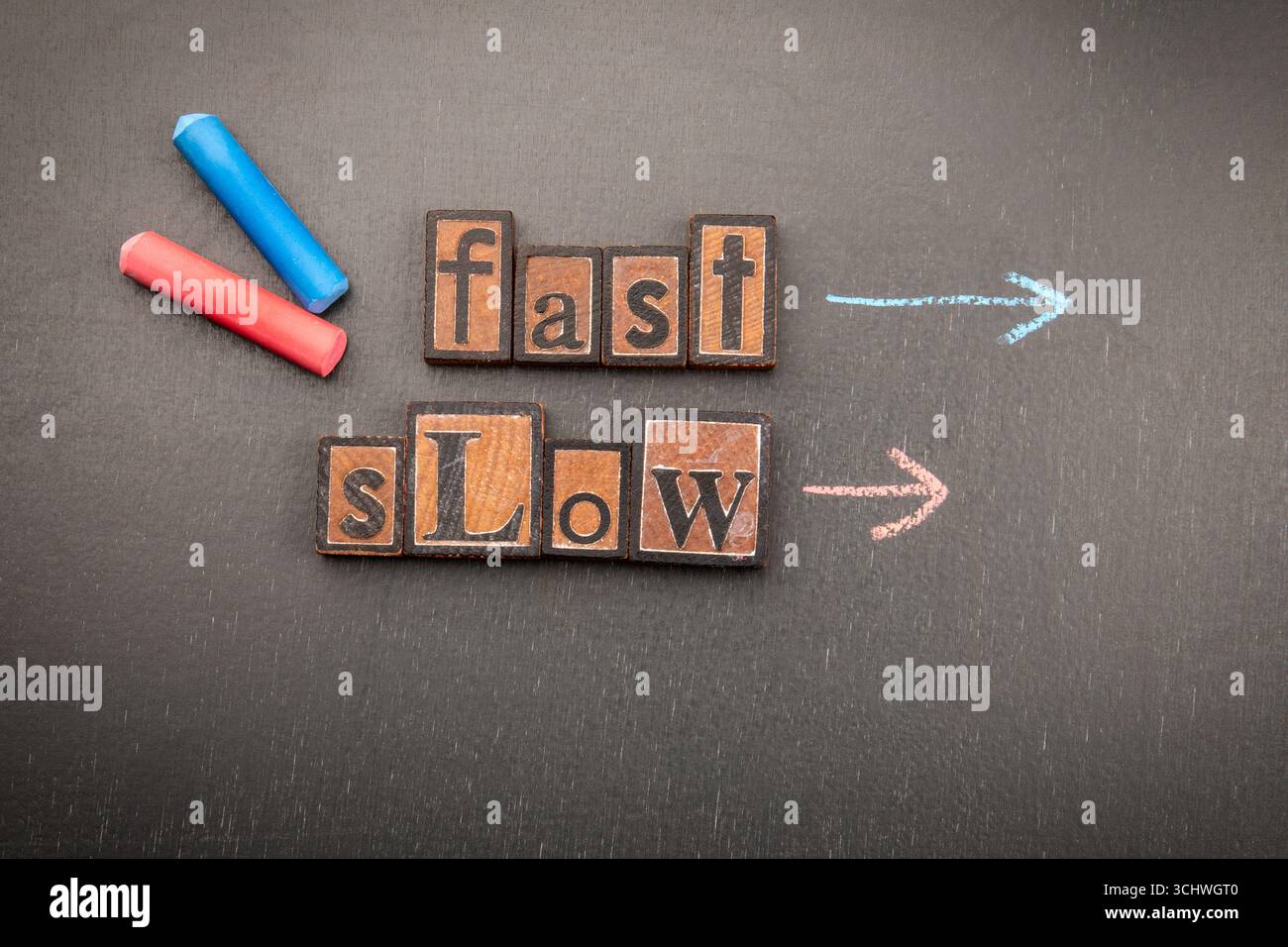 Concept of fast versus slow with chalk arrows and wooden letter blocks ...