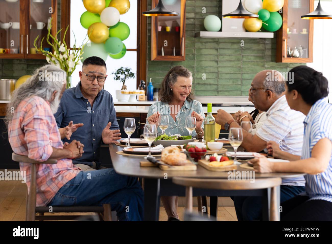 Diverse senior friends enjoying lunch and conversation at home around ...