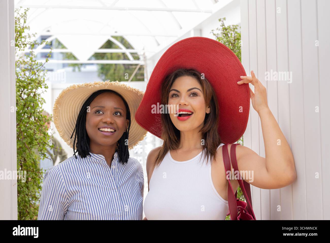 Two women wearing sun hats smiling outdoors, enjoying sunny day ...