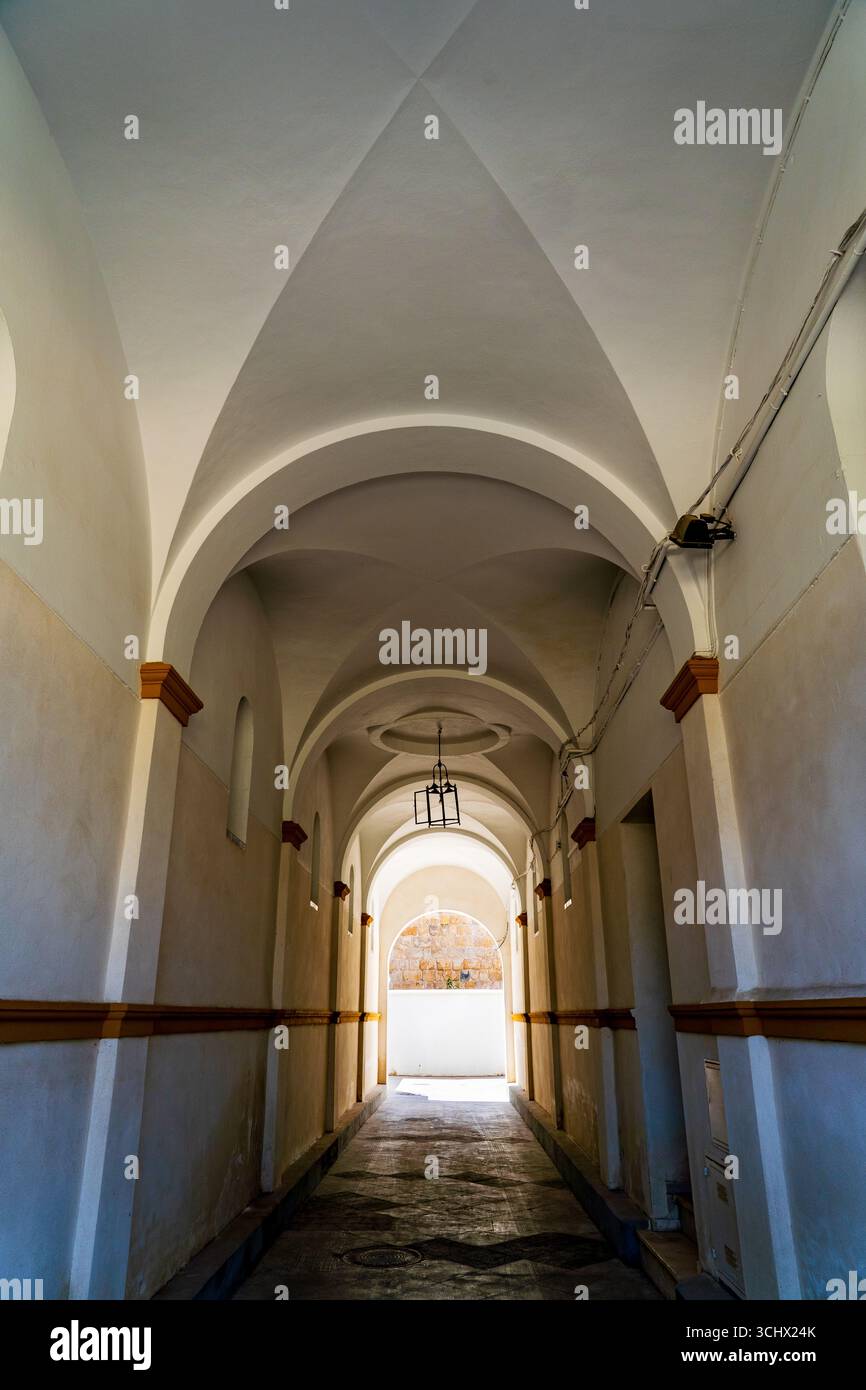 Historic arched passageway with vaulted ceiling, lantern light, and ...