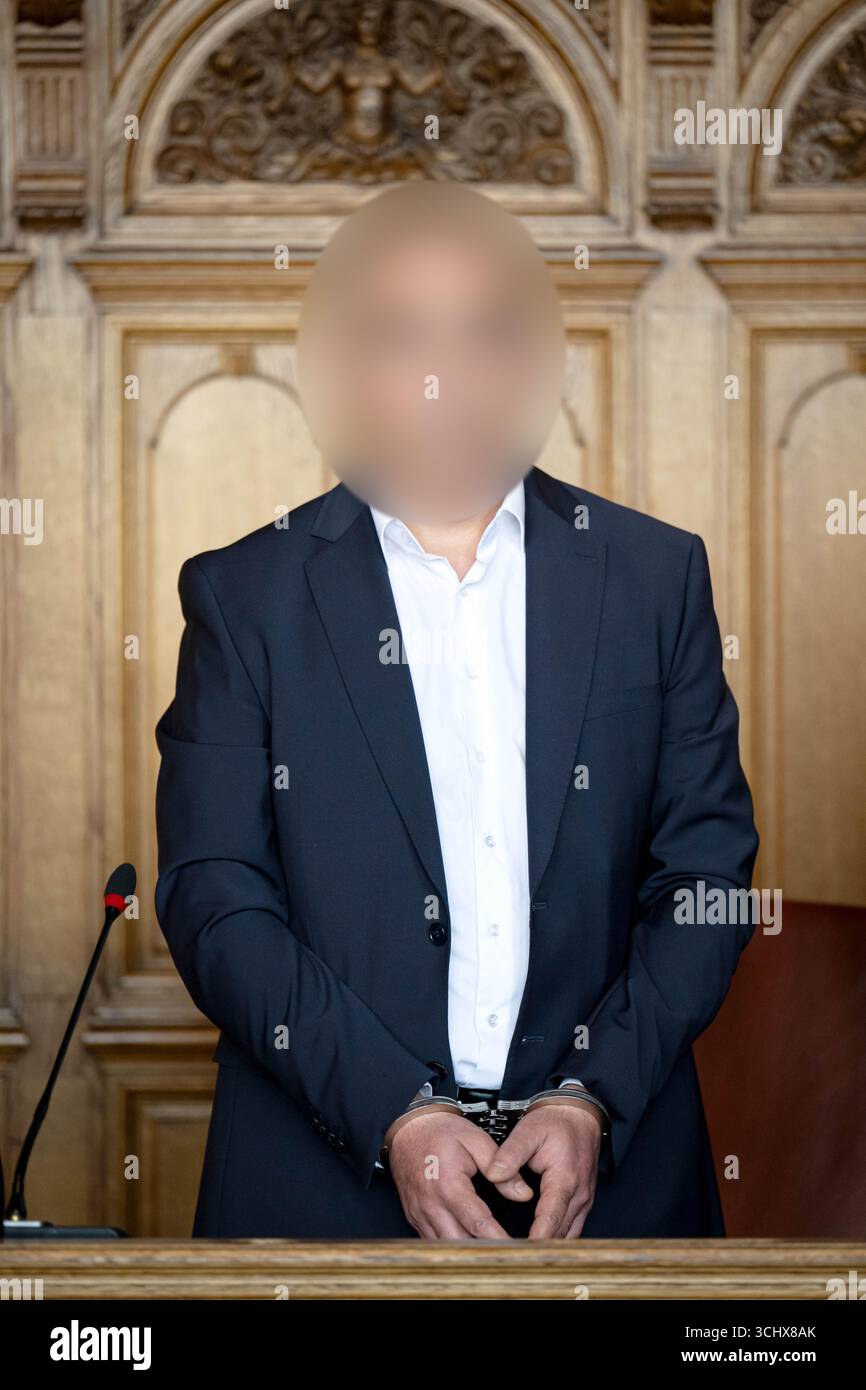 04 September 2025, Bremen: The defendant stands handcuffed in the ...