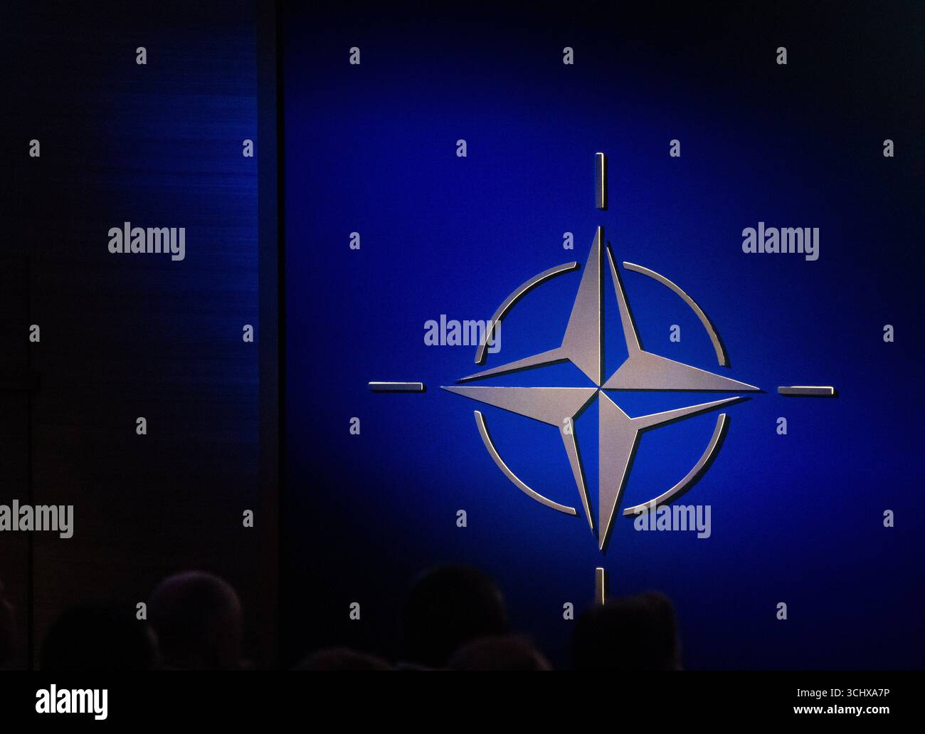The NATO logo is illuminated beside the stage during a ceremony ...