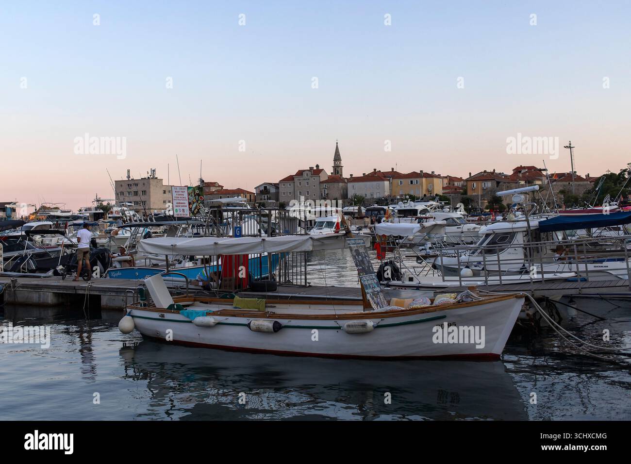 Marina in Budva Bay with boats and view of the Old Town at sunset ...