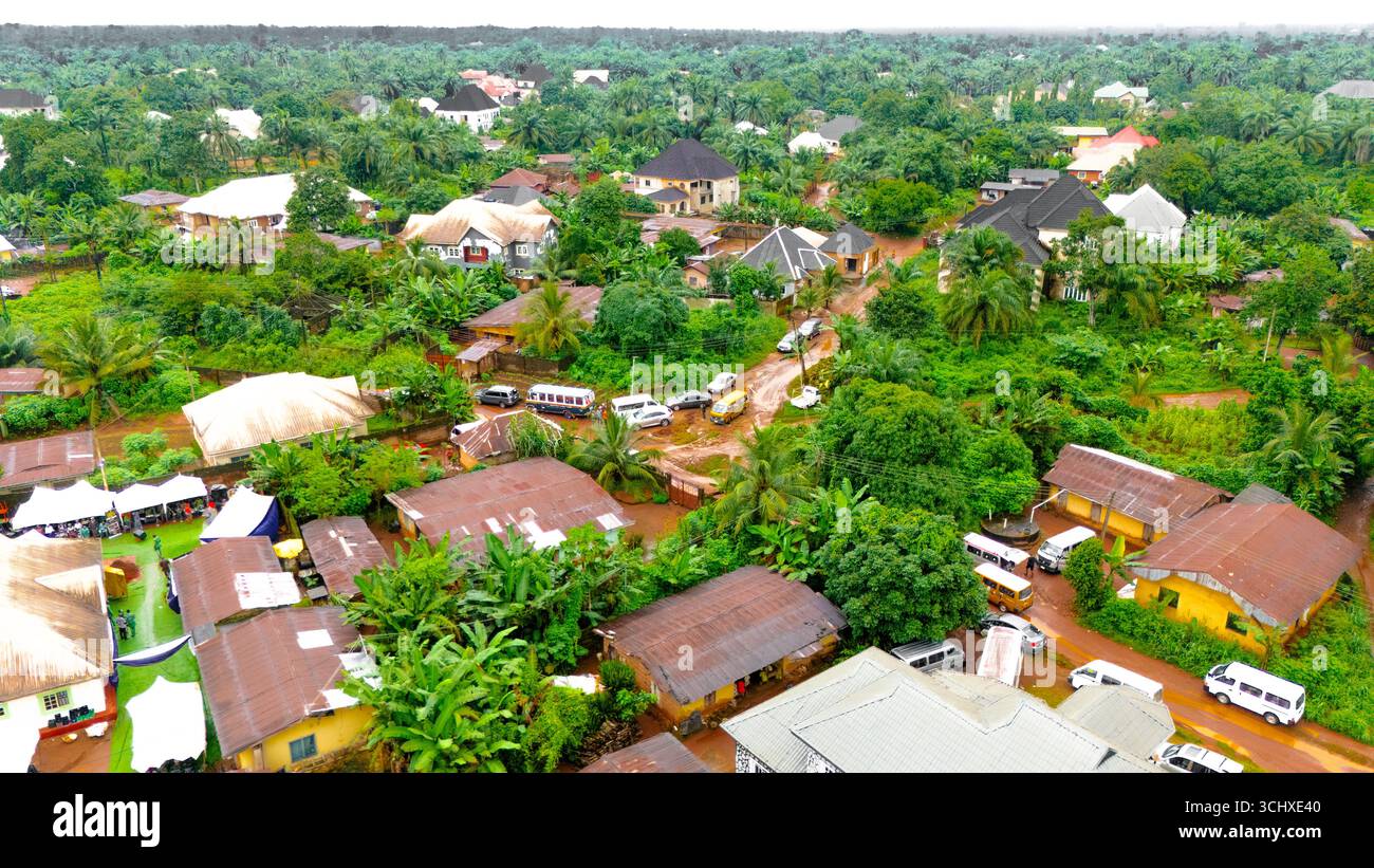 Aerial view of a Okwele Community with cars and buses amidst lush green ...