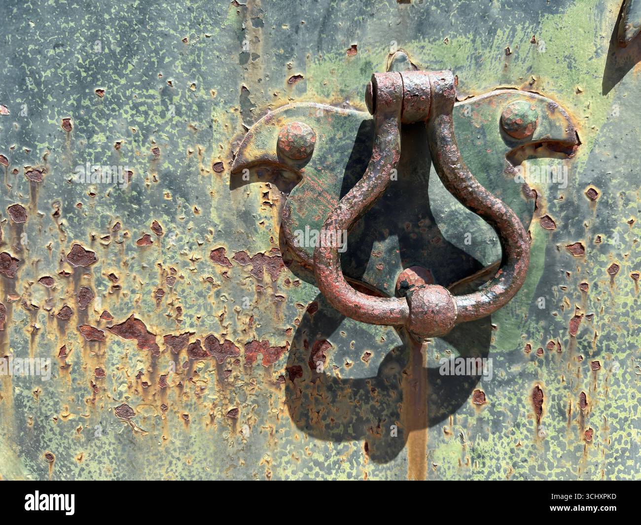 Rusty metal door with flaking paint and weathered hinges, capturing ...