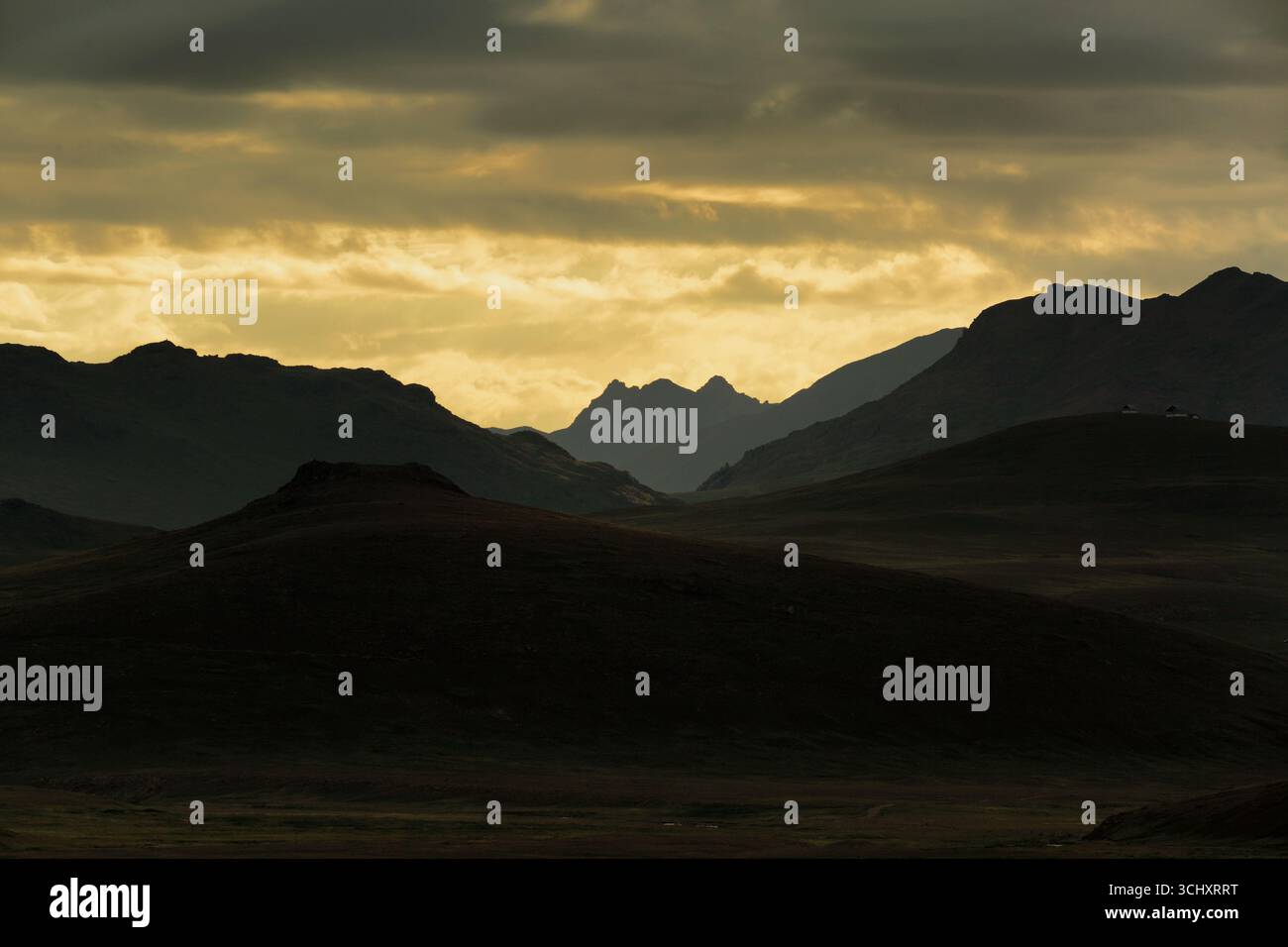 View of dark, rolling hills and distant, jagged mountains silhouetted ...