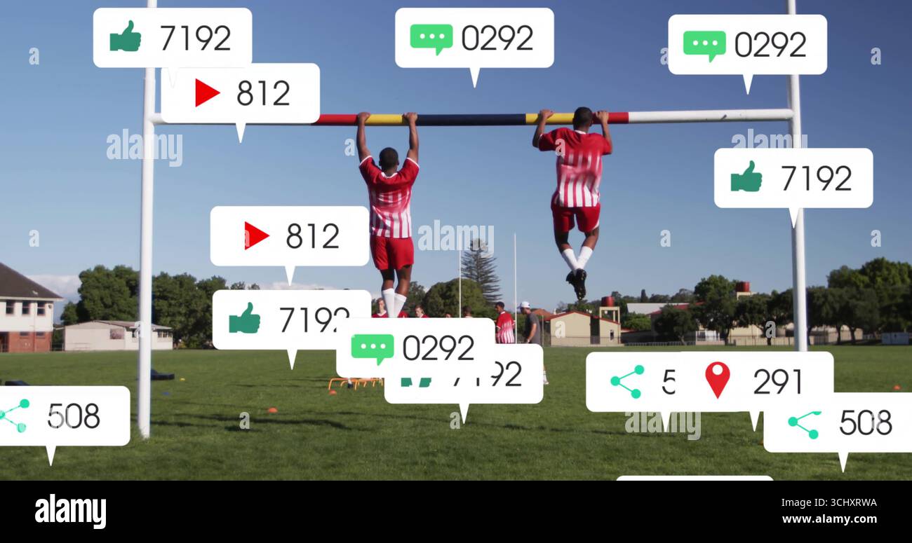 Training soccer players gripping pull-up bar on suburban field, pulling ...
