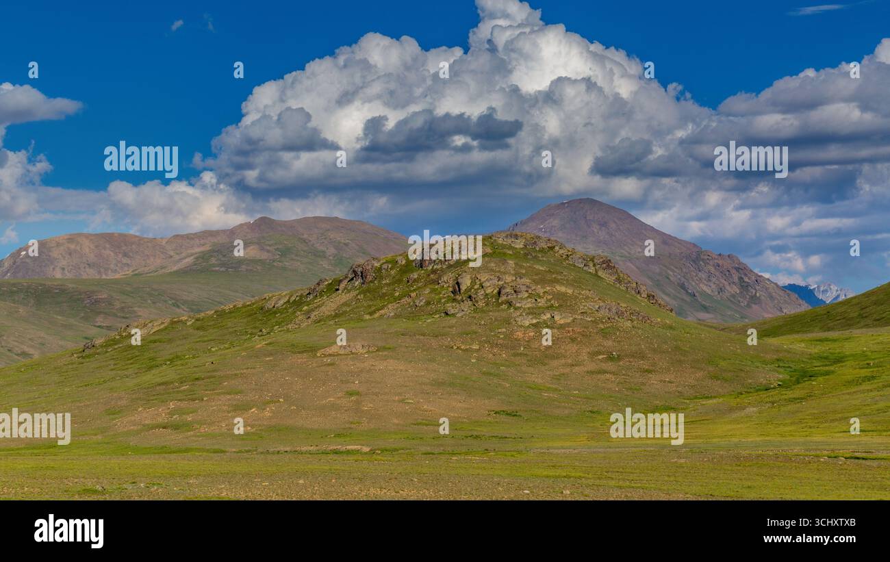 View of rolling green hills meet rugged mountains under a vast sky ...