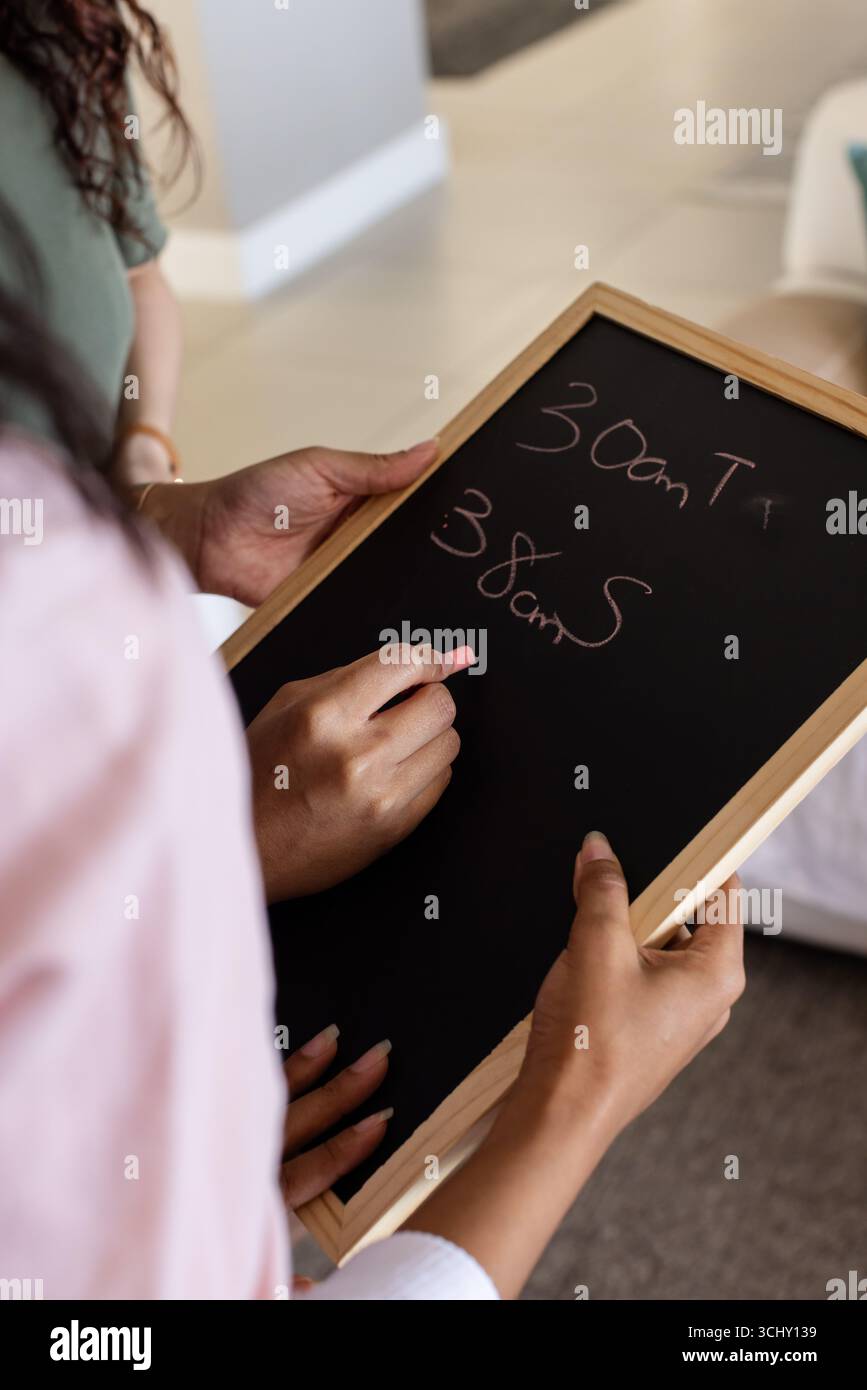 Writing measurements on chalkboard, hands holding chalk, focusing on ...