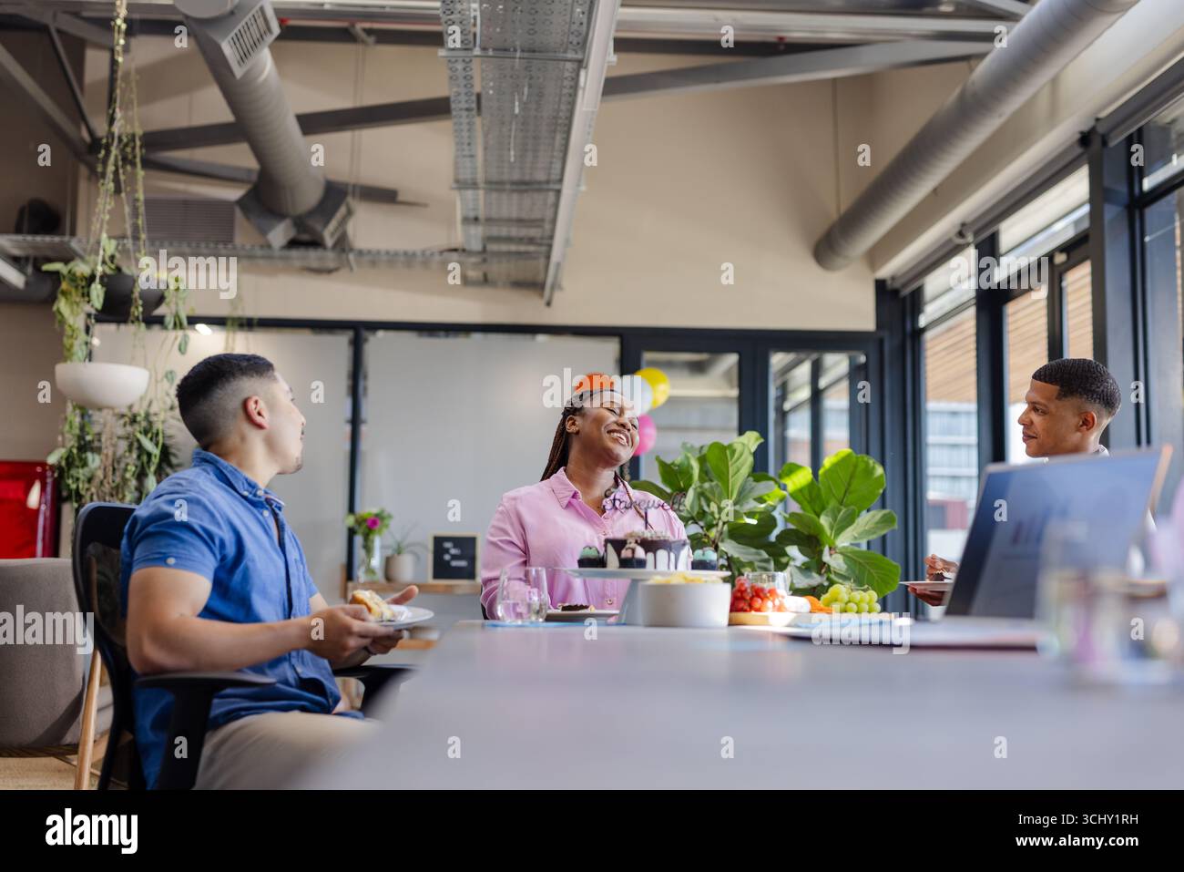 Colleagues enjoying lunch and conversation in modern office break room ...
