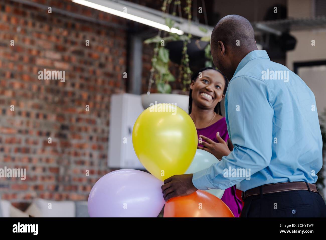 Smiling colleagues holding colorful balloons, celebrating in modern ...