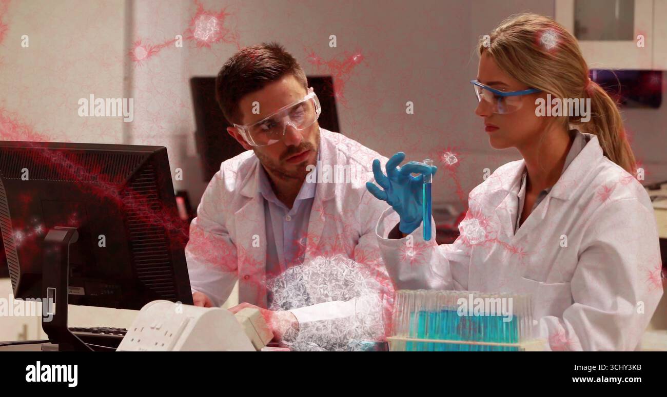 Researchers wearing safety gear examining blue liquid test tube at lab ...