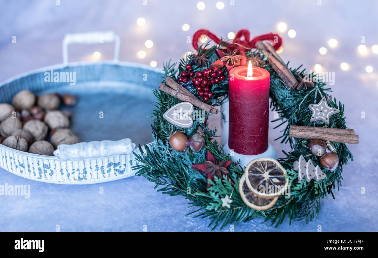 Christmas wreath with burning red candle next to a tray of nuts Stock ...