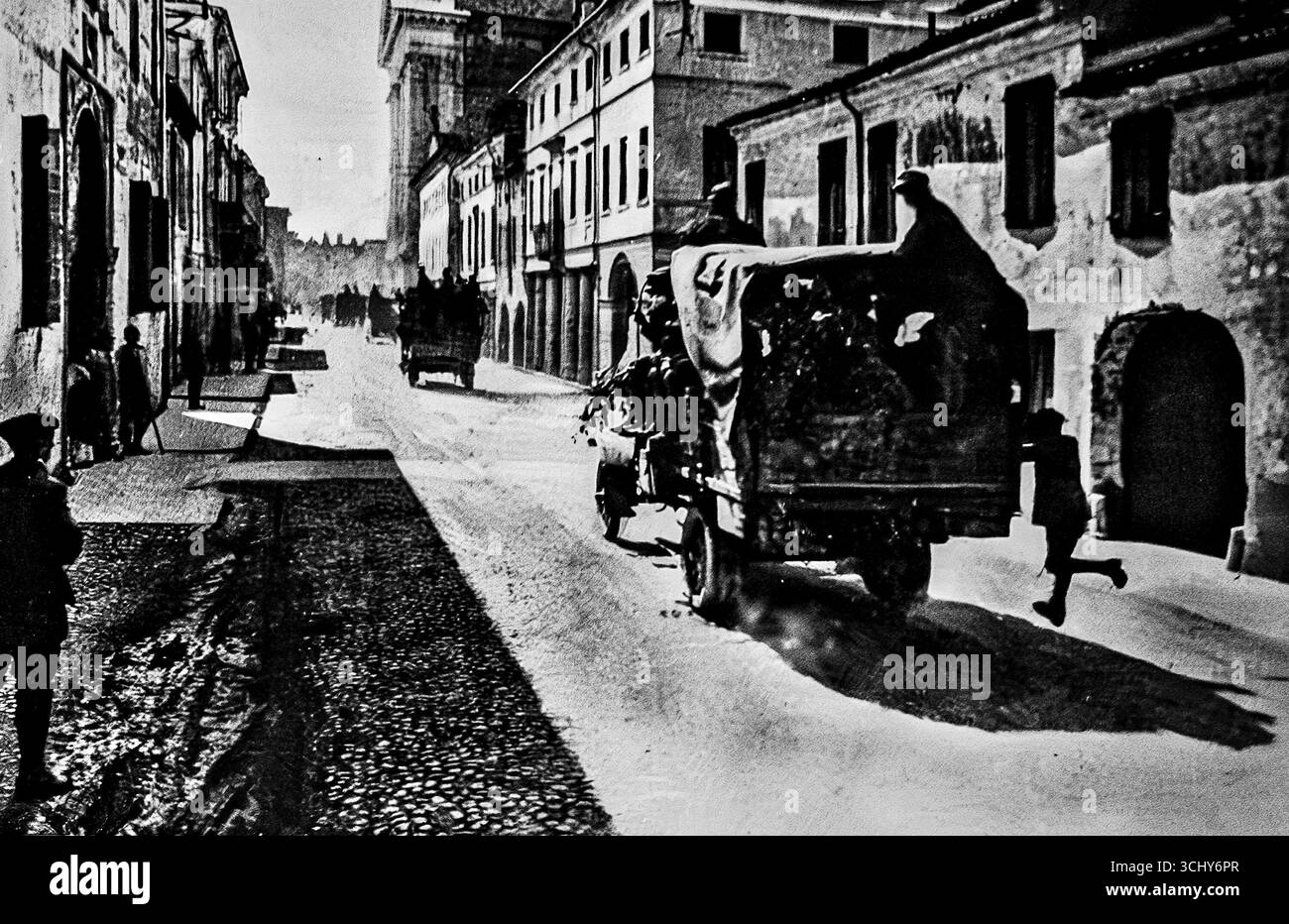 Black and white photo of an Italian military convoy crossing a town in ...