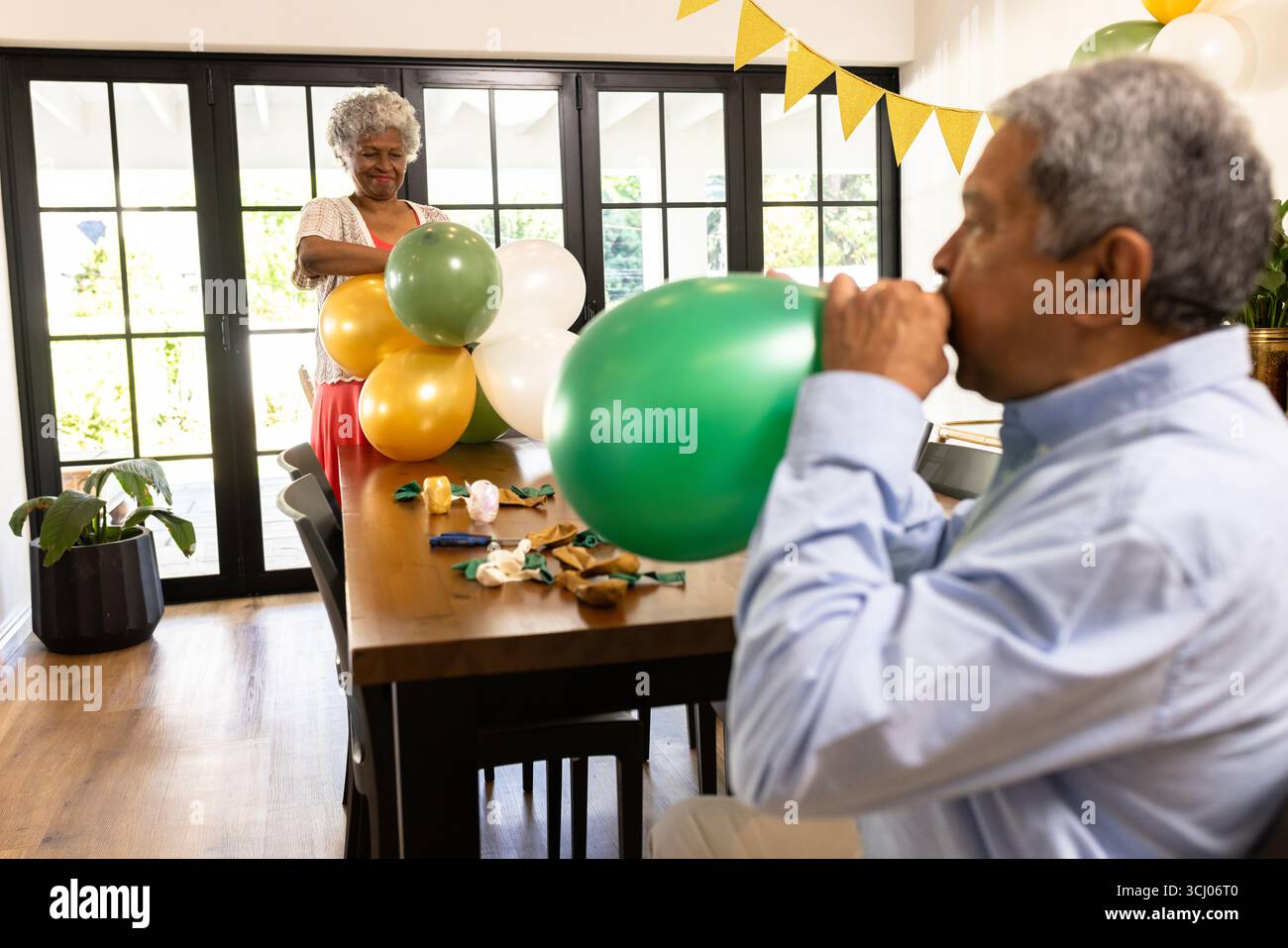 Senior diverse senior couple decorating with balloons for party ...
