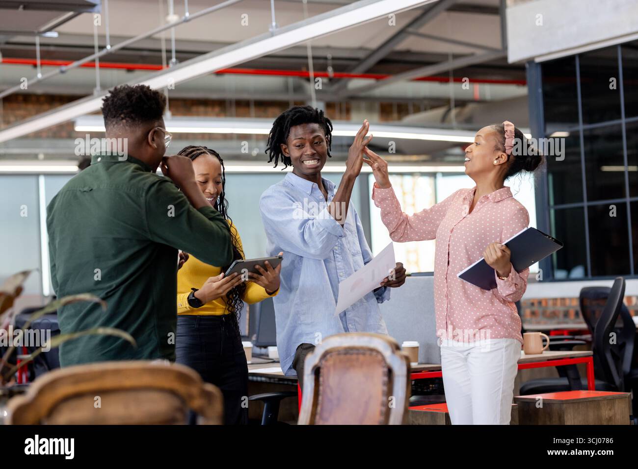 Team celebrating success in modern office, high-fiving and smiling with ...