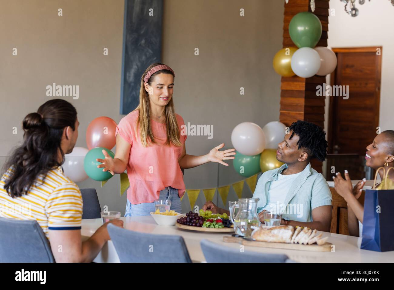 At home, woman talking while friends standing and listening ...