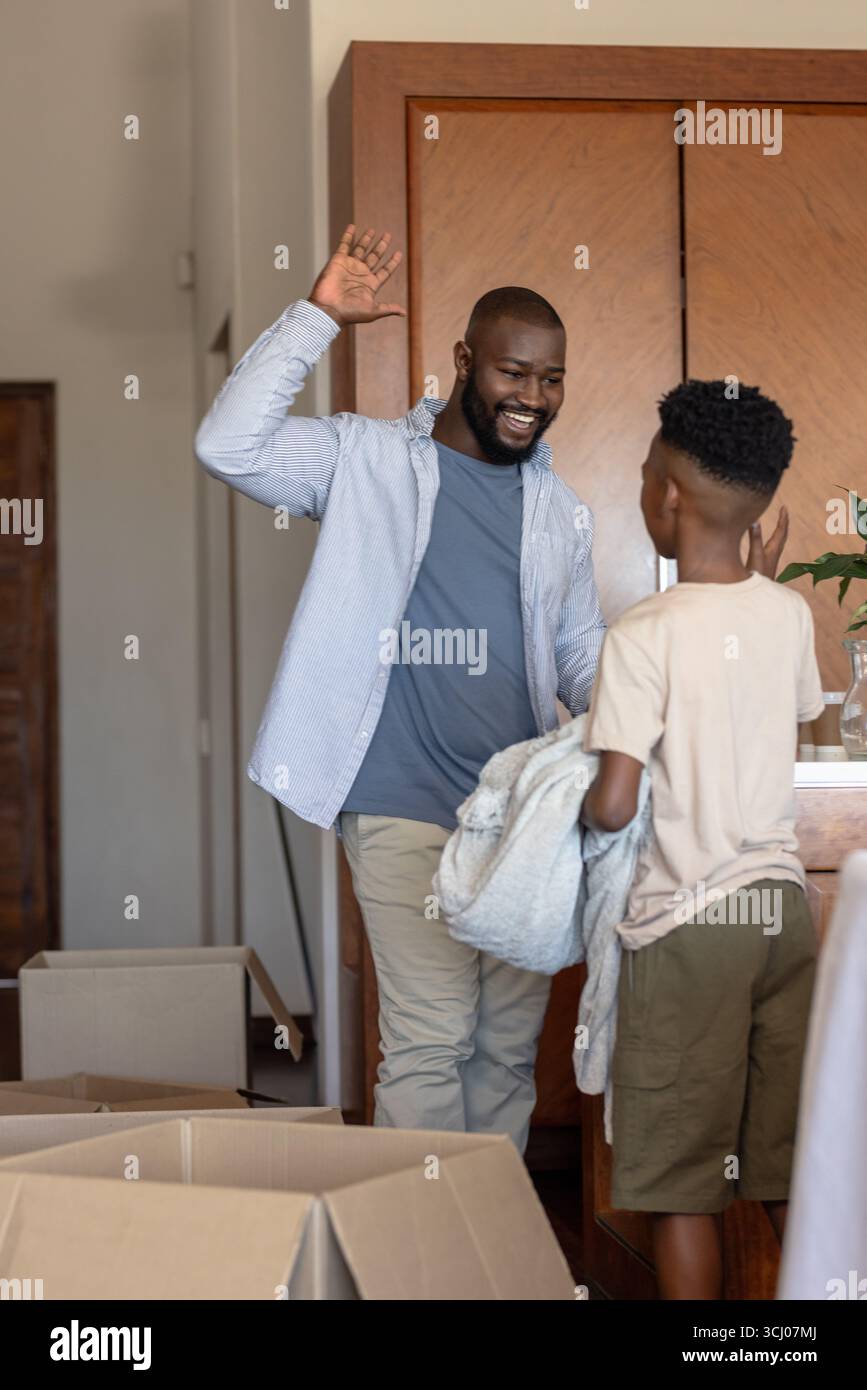 Father and son unpacking boxes at home, sharing joyful high-five Stock ...