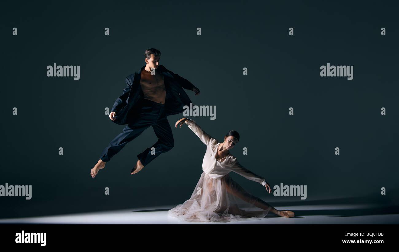 Male dancer leaping high as female ballerina bends gracefully Stock ...