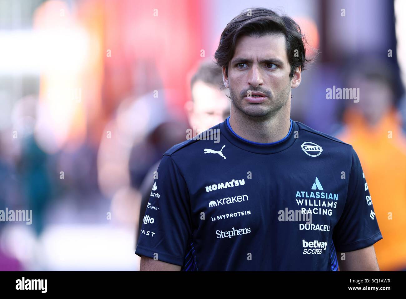 Carlos Sainz of Williams Racing looks on in the Paddock during previews ...