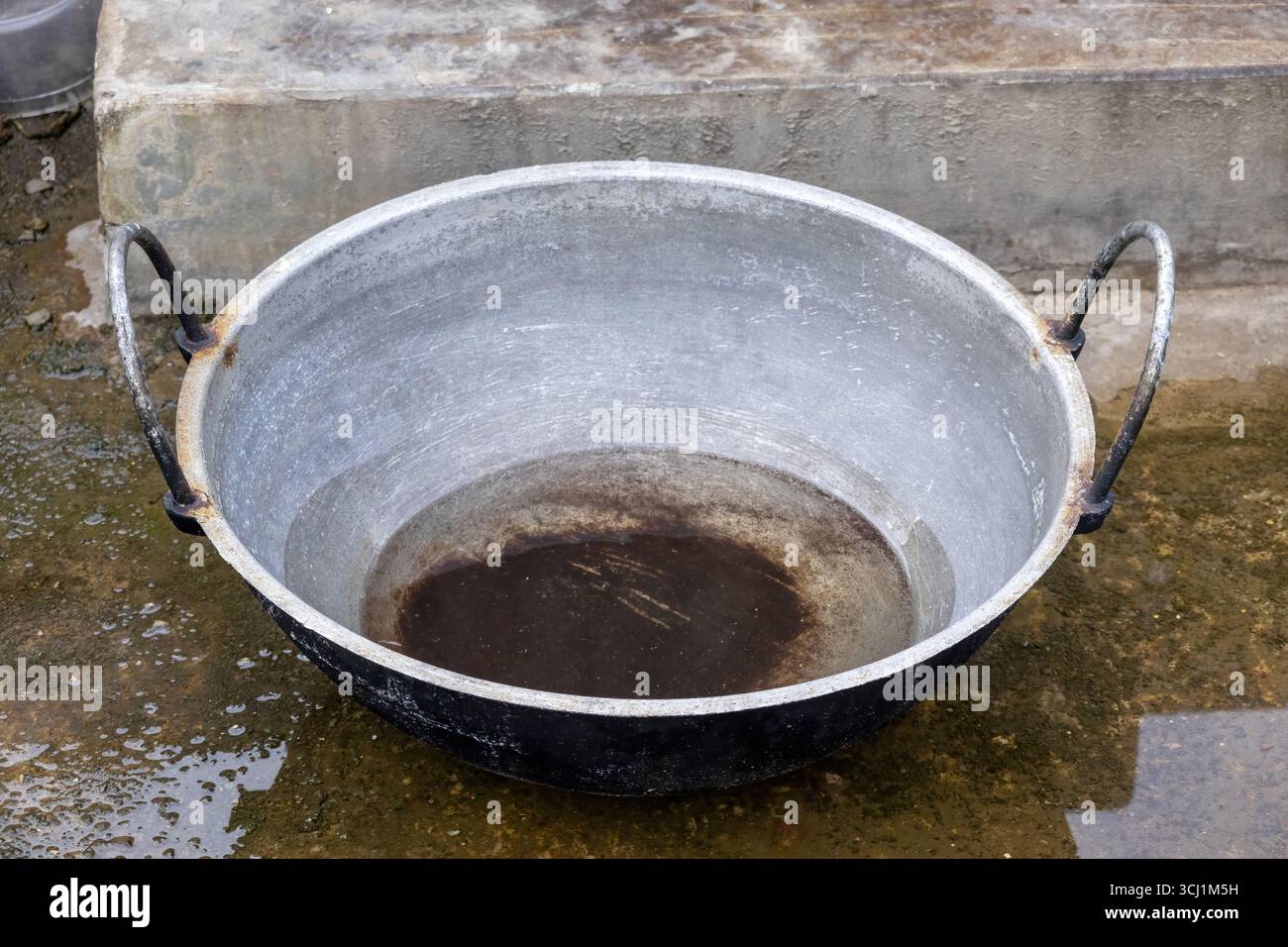 A cast-iron kadai (or karahi) after cooking, sitting on a weathered ...
