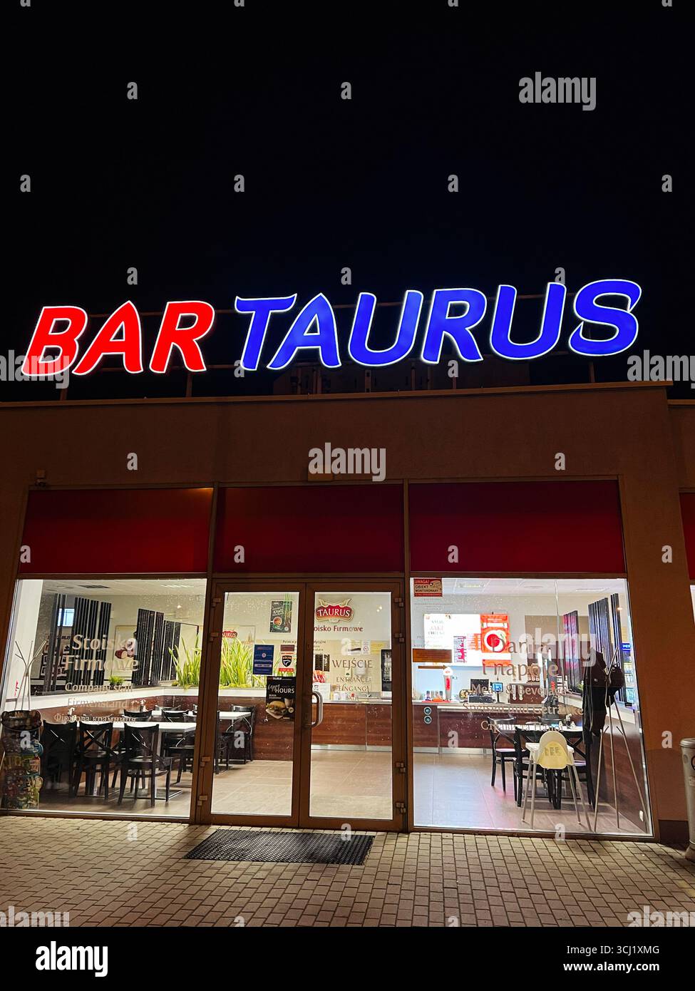 Krakow, Poland - July 08, 2025: Brightly lit bar Taurus entrance ...