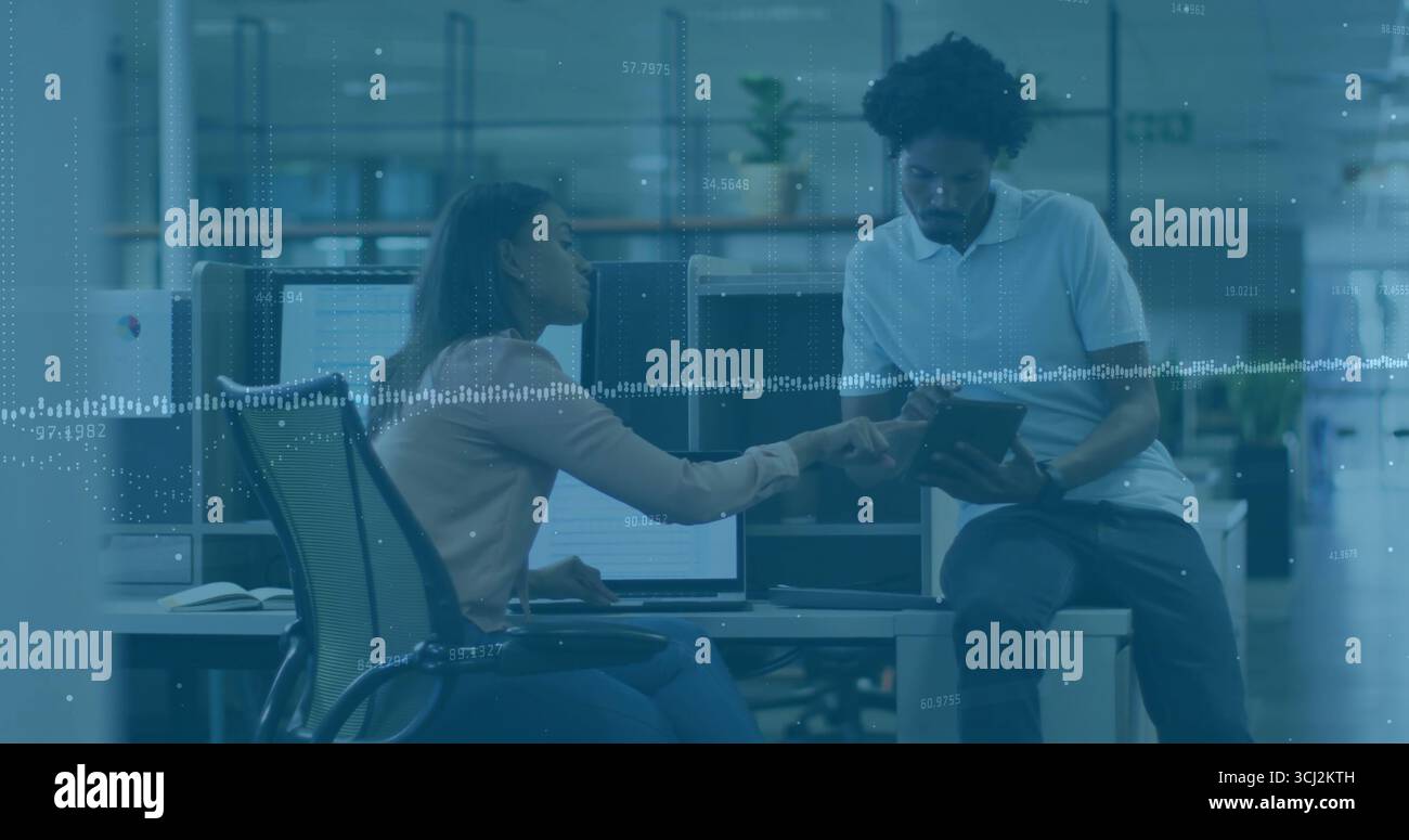 Pointing woman guiding coworker through tablet data in modern open-plan ...