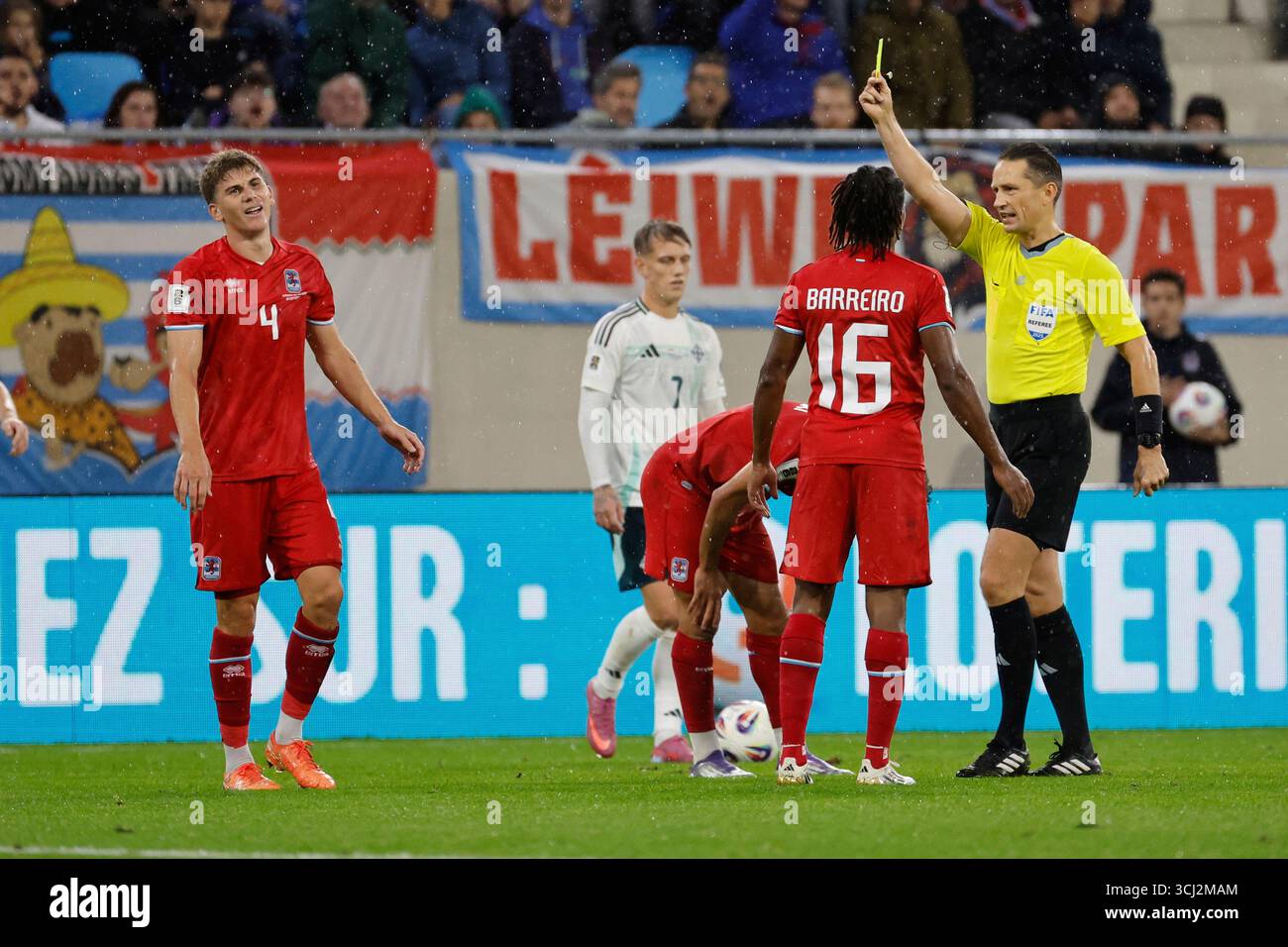The referee shows a yellow card for Luxembourg's Florian Bohnert, left ...