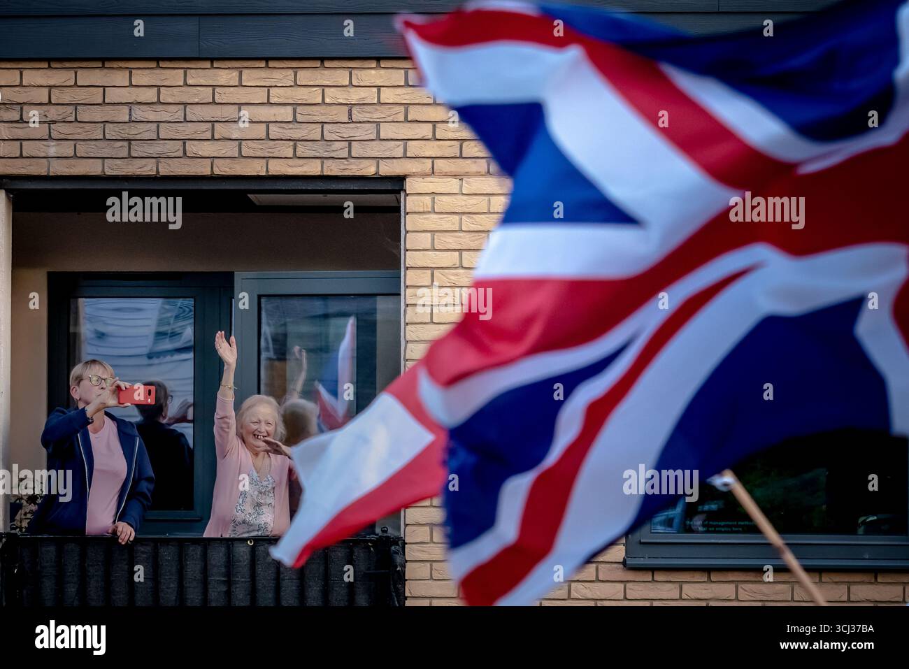 Local residents wave from windows in a show of support to the marching ...