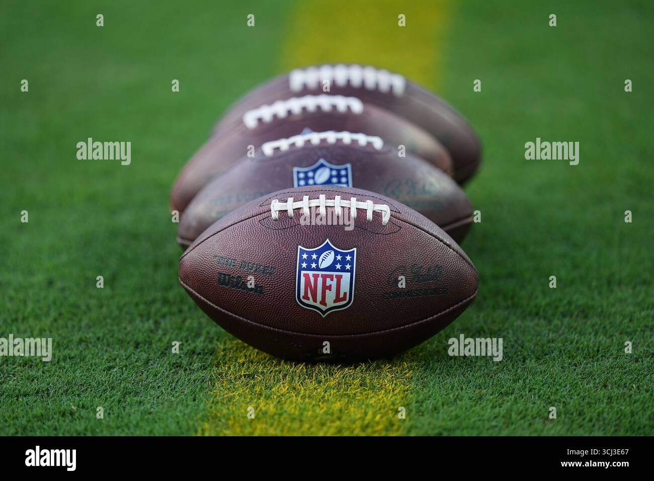 Footballs are lined up on the field before an NFL football game between ...
