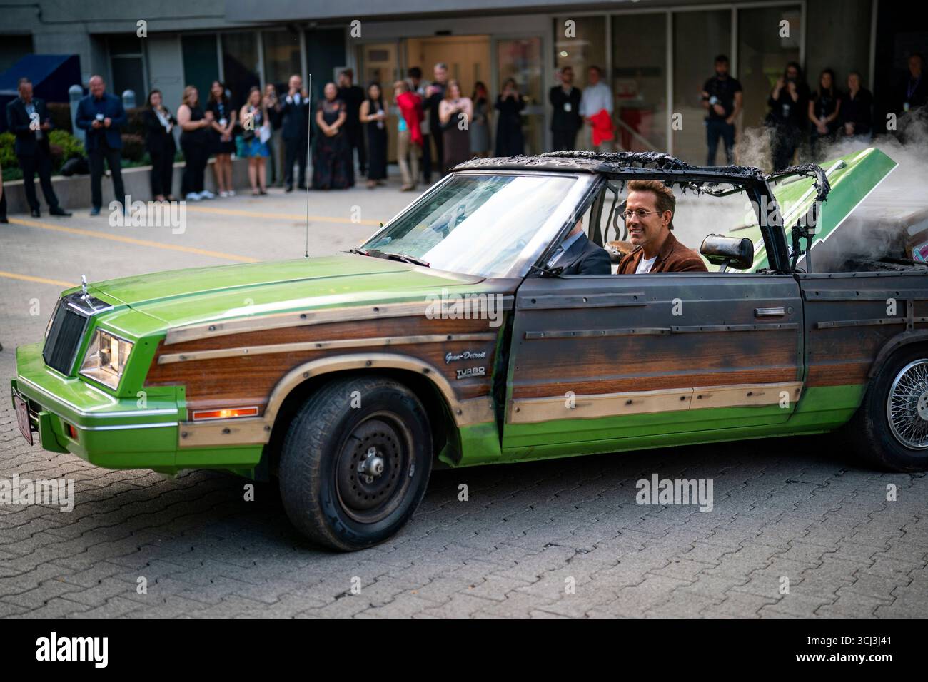 Producer Ryan Reynolds and director Colin Hanks drive in a replica prop car from the movie ...