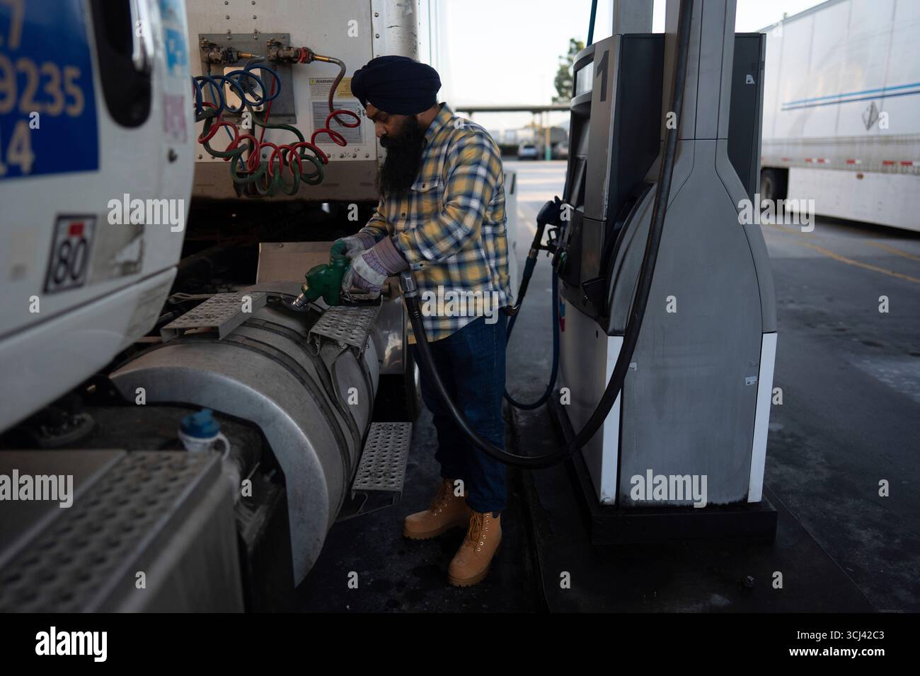 Sikh truck driver Prahb Singh fills up the tank of his truck at a gas ...
