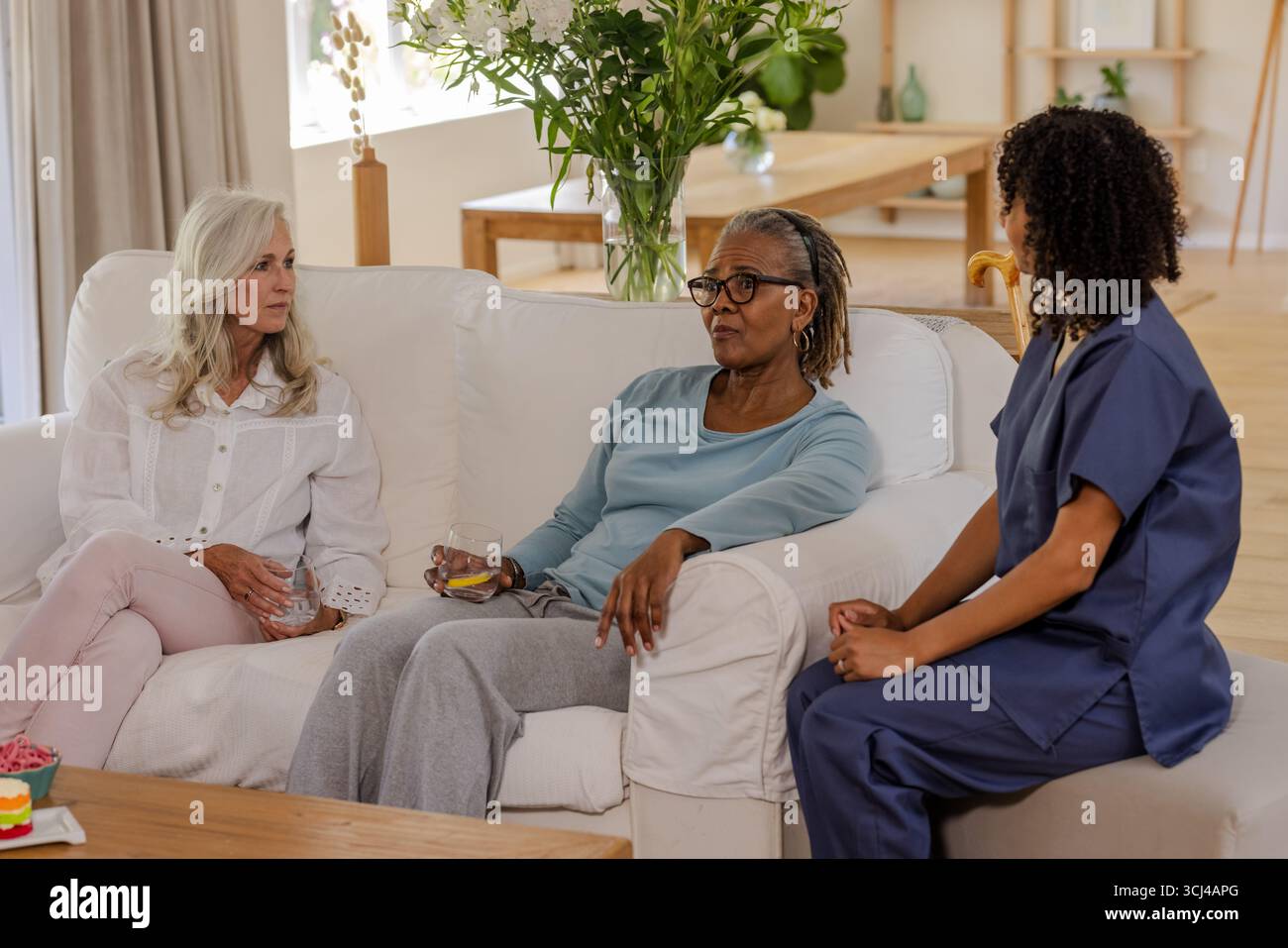 Senior friends relaxing on sofa, enjoying conversation with healthcare ...