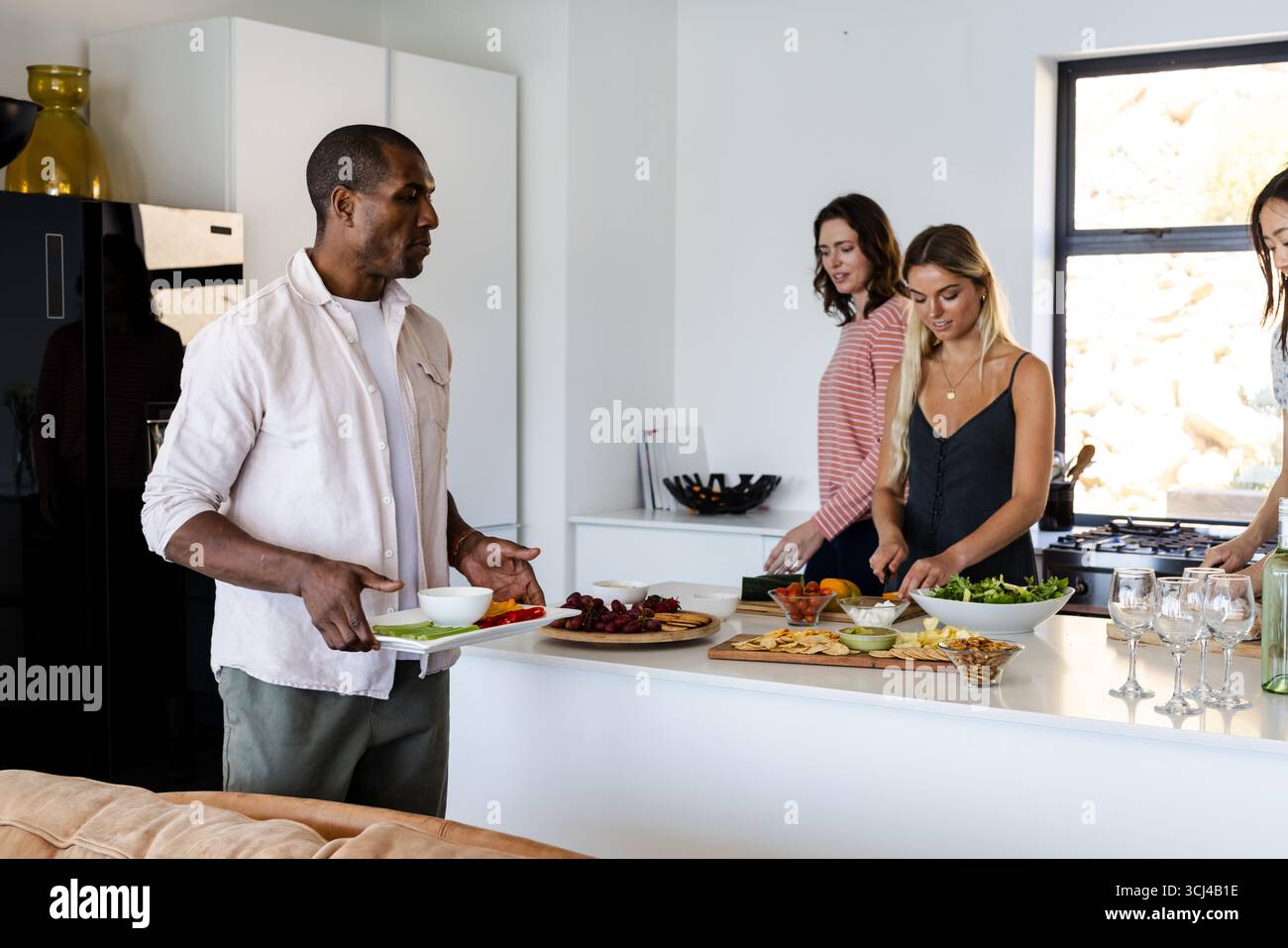 African American man serving food while friends prepare dishes in ...