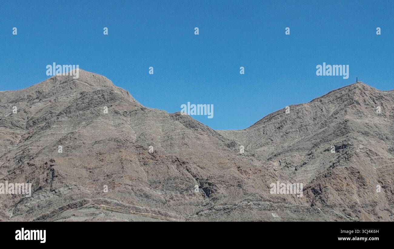 Aerial view of rugged mountains under a clear blue sky, their peaks and ...