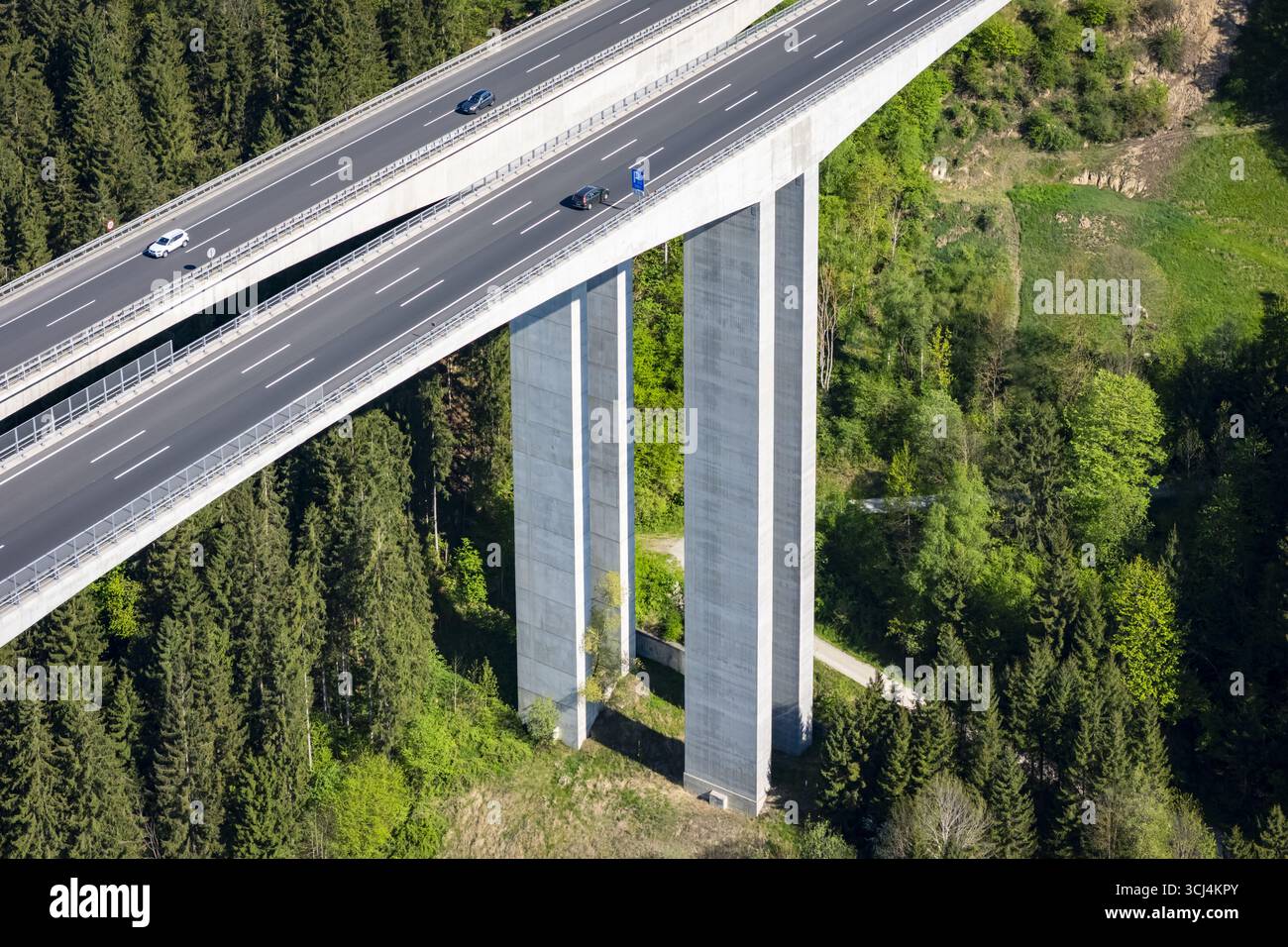 Aerial view of a concrete highway bridge soaring over a dense forest ...