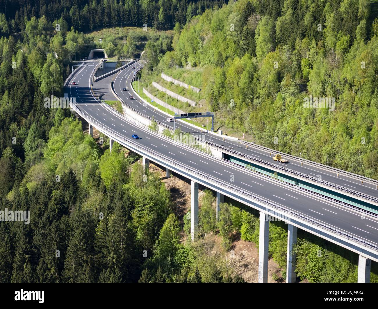 Aerial view of a ribbon of highway cutting through the verdant forest ...