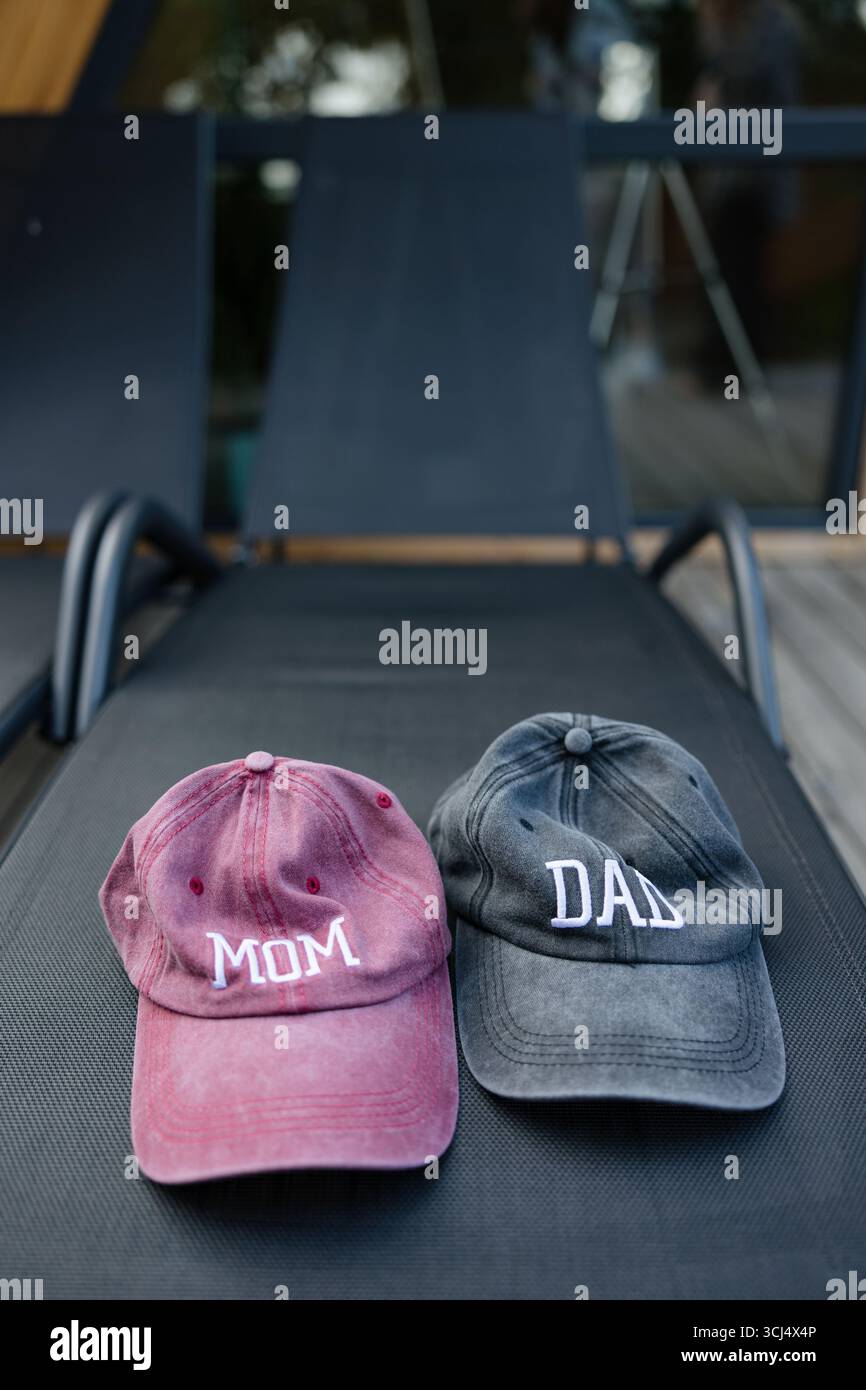 Two well-worn caps labeled 'MOM' and 'DAD' sit side by side on a lounge ...