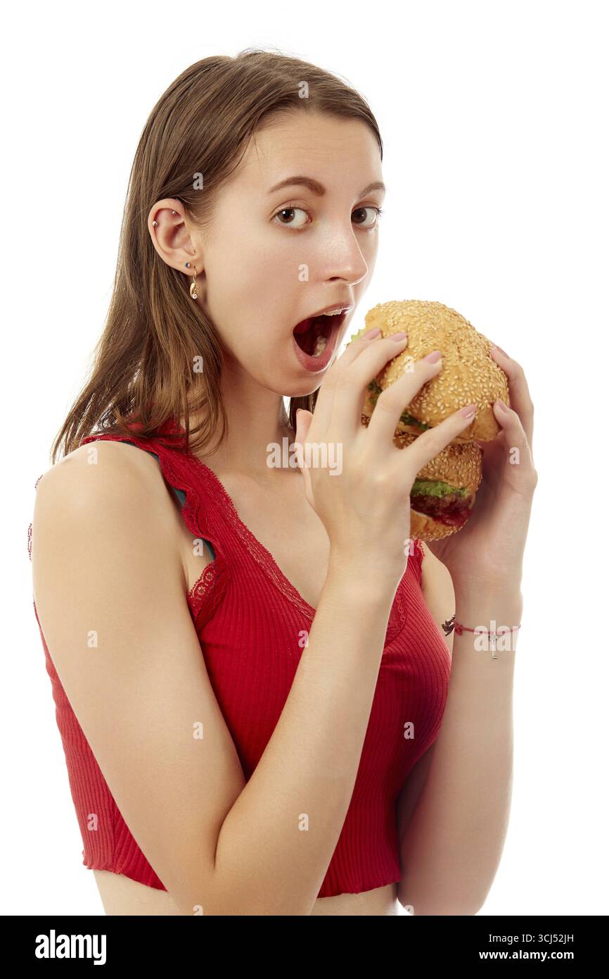 Happy young woman eats cheeseburger on white background isolated ...