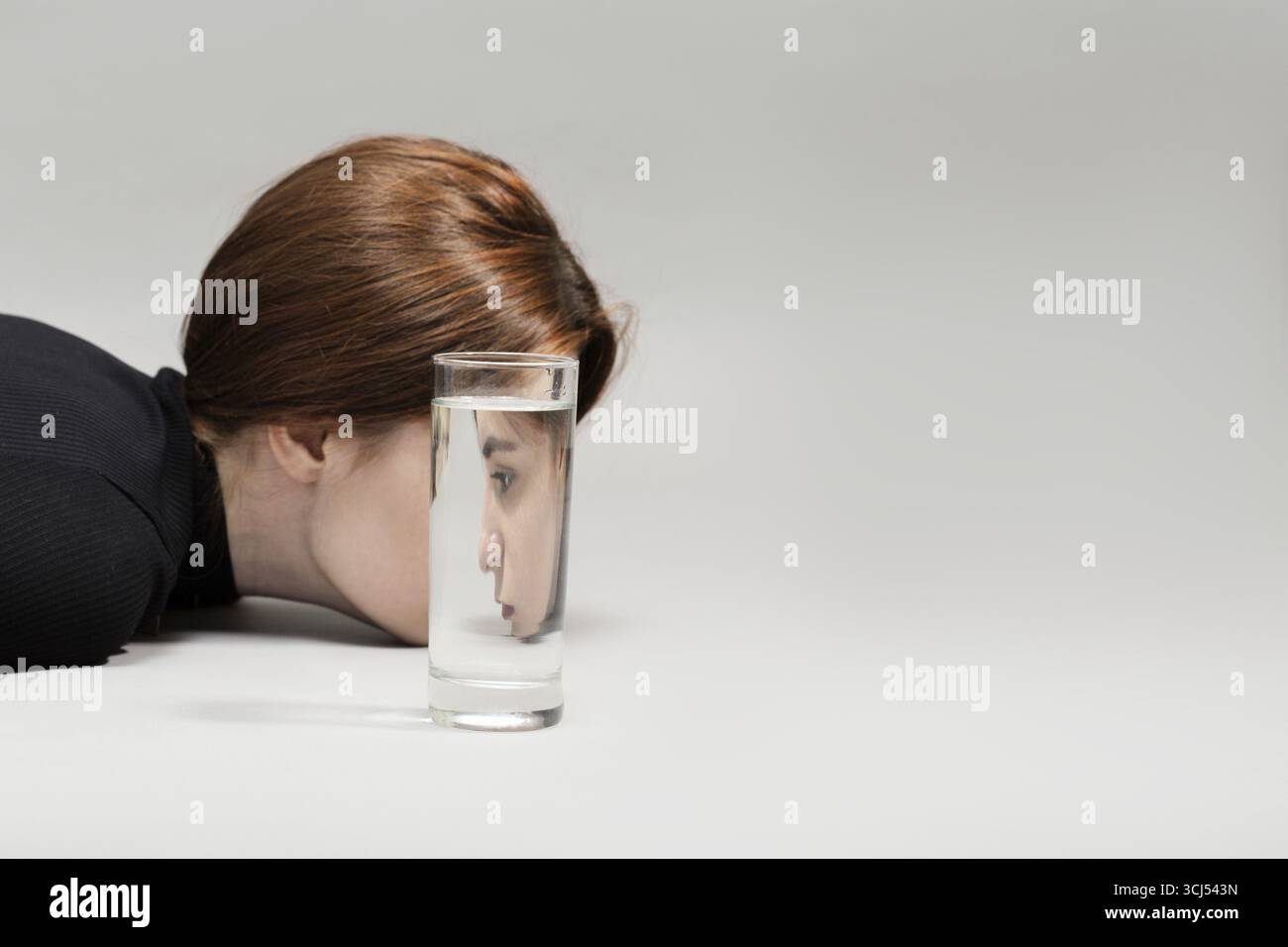 Sad girl profile and glass with water on gray background with copy ...
