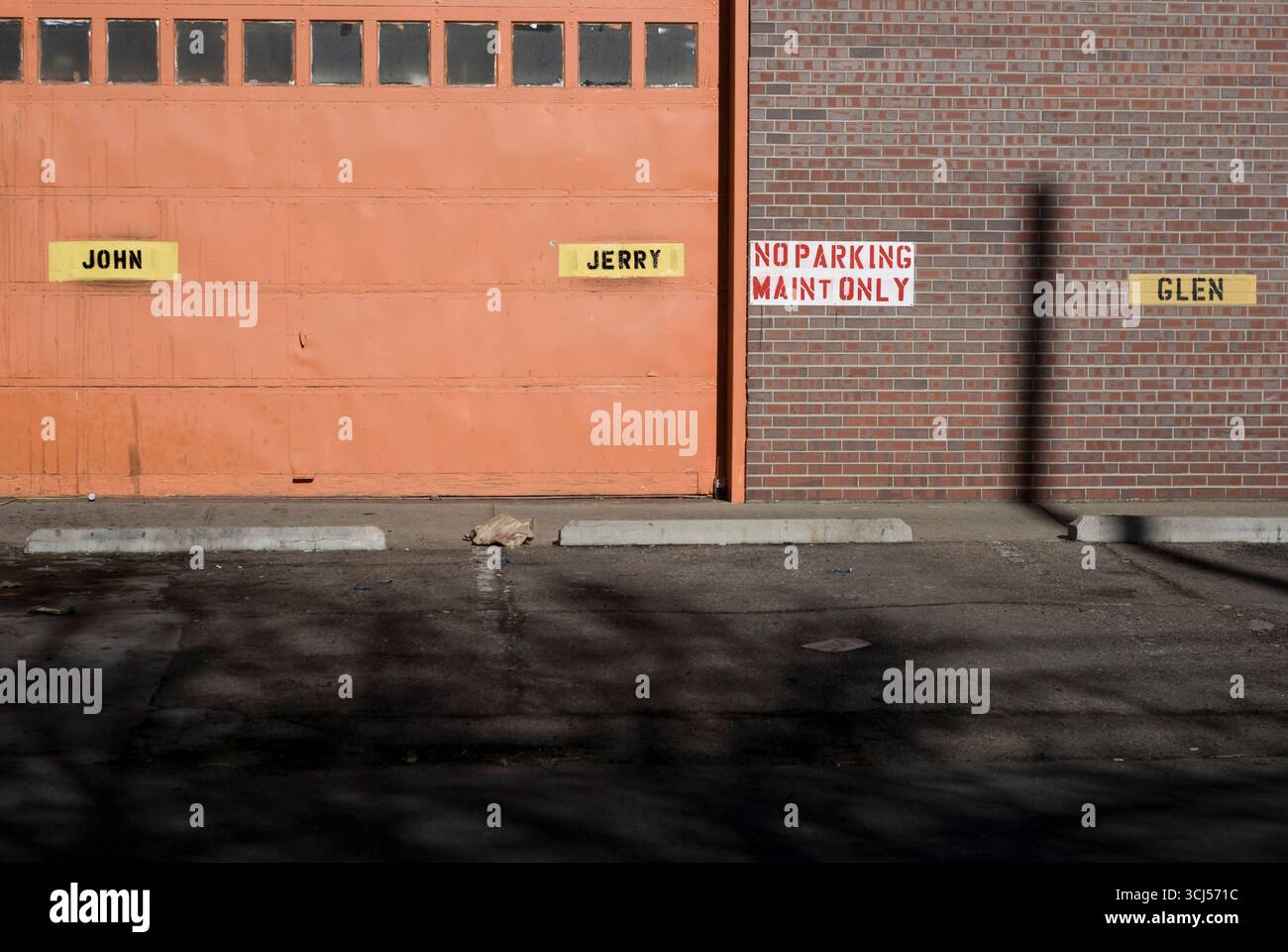 Assigned parking spaces are marked with name tags hung on a brick wall ...