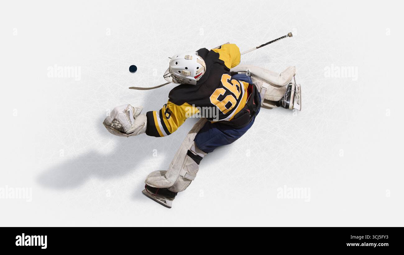 Overhead view hockey goalkeeper in yellow jersey leaping to block puck ...