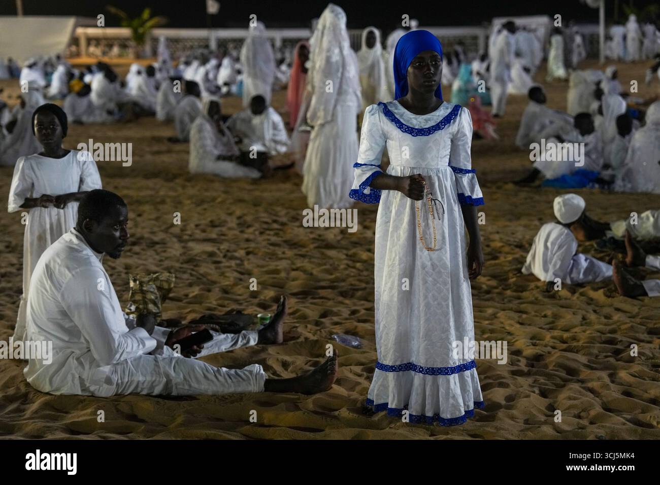A girl dressed in a white gown holds prayer beads as people mark ...