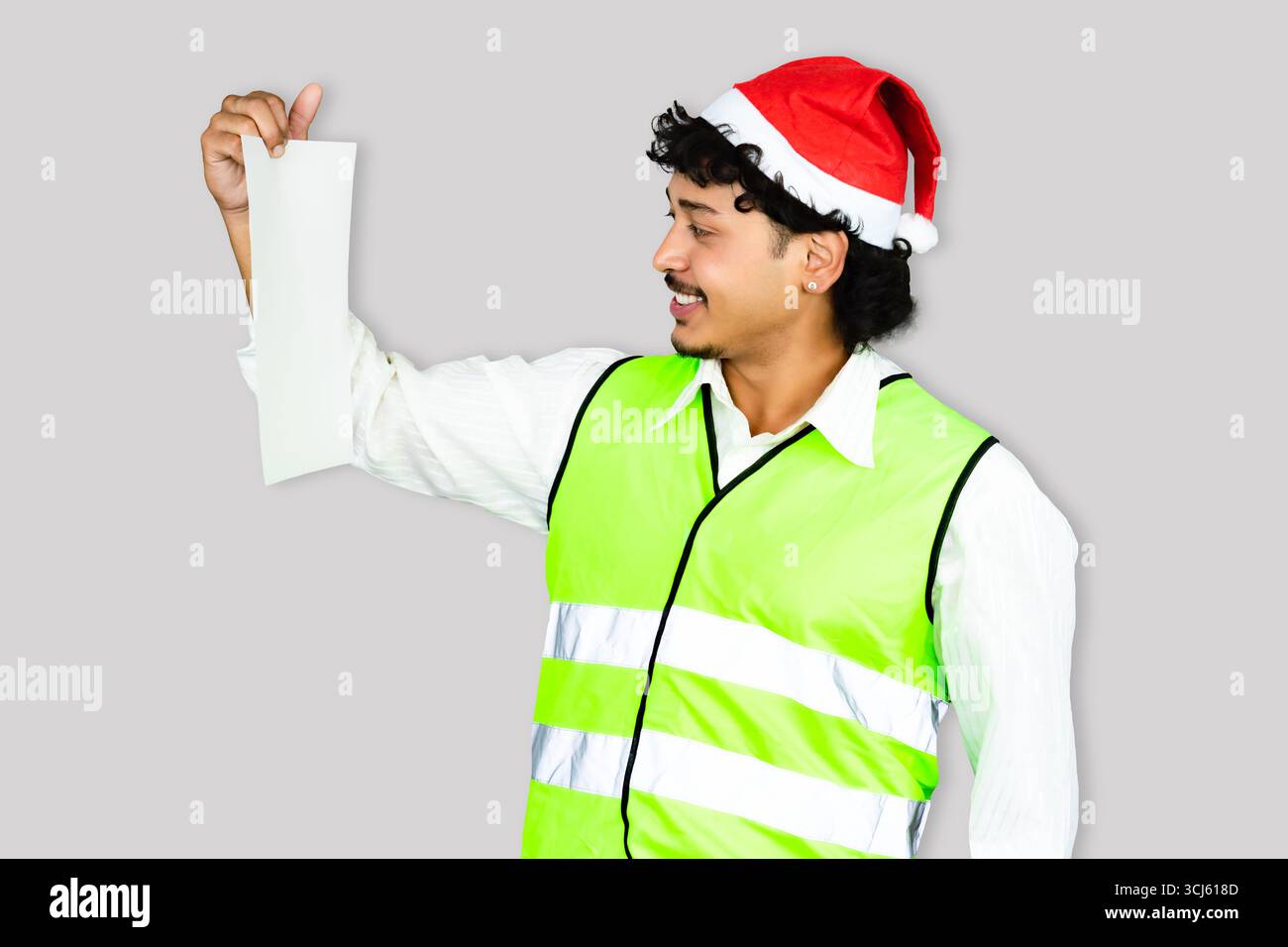 Young male construction worker wearing a Santa Claus hat and light-up ...