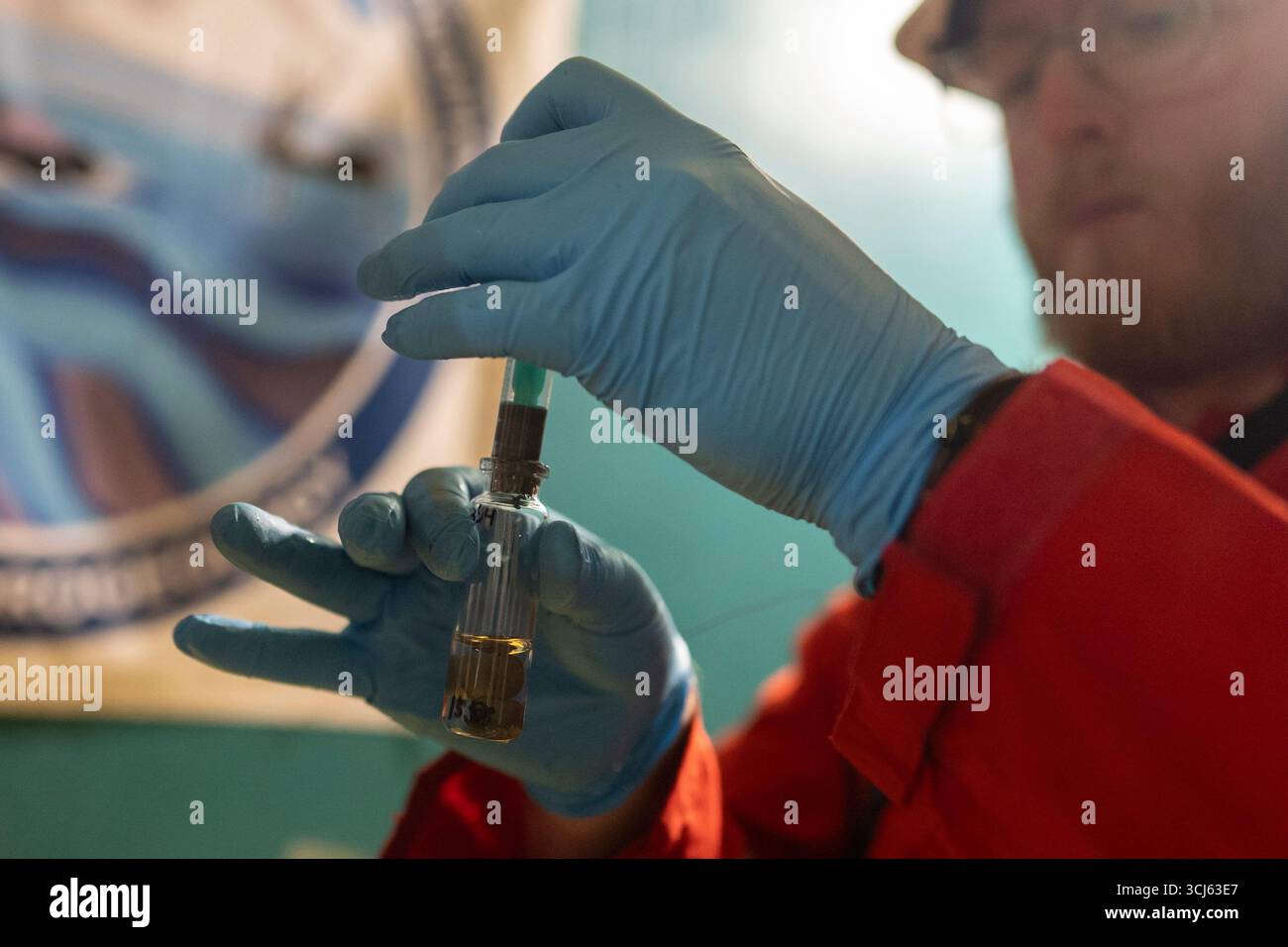Expedition 501 researcher Jack Brickell puts a sediment sample in a ...