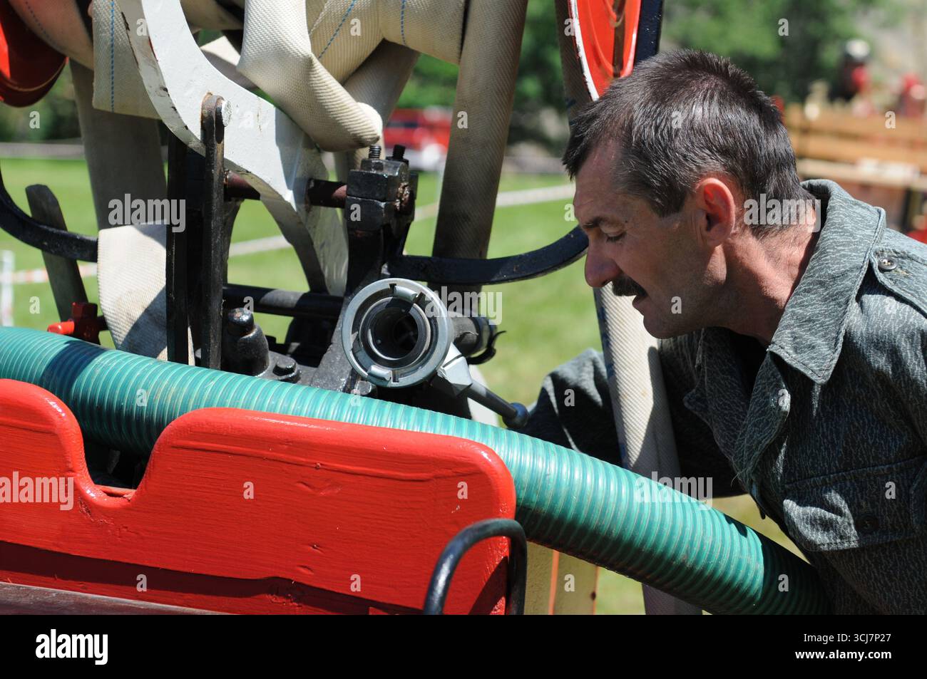 Firefighter inspecting antique horse-drawn fire pump during heritage ...